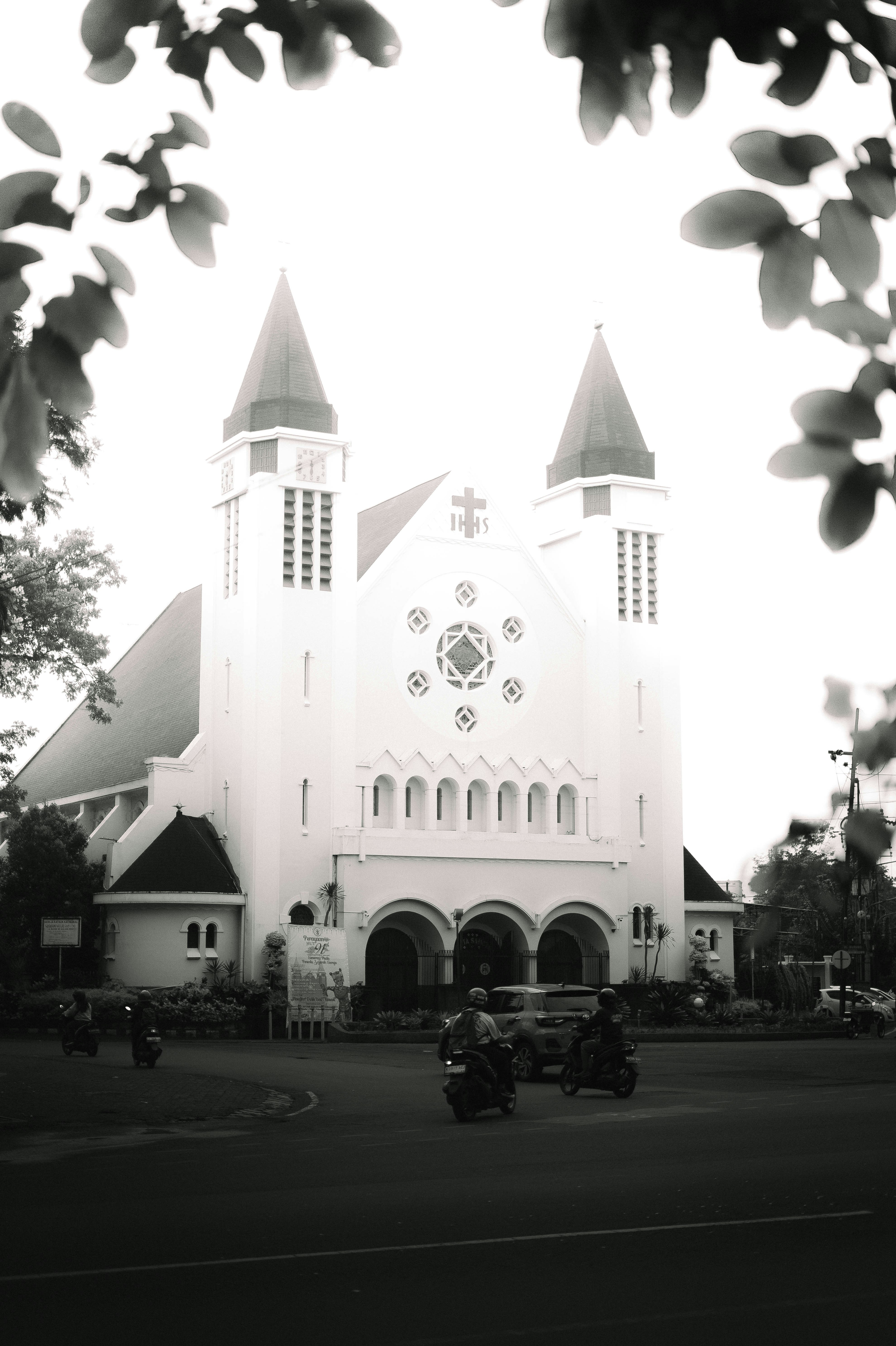 Twin Spires and a Rose Window: A Bright Church Framed by Leafy Border