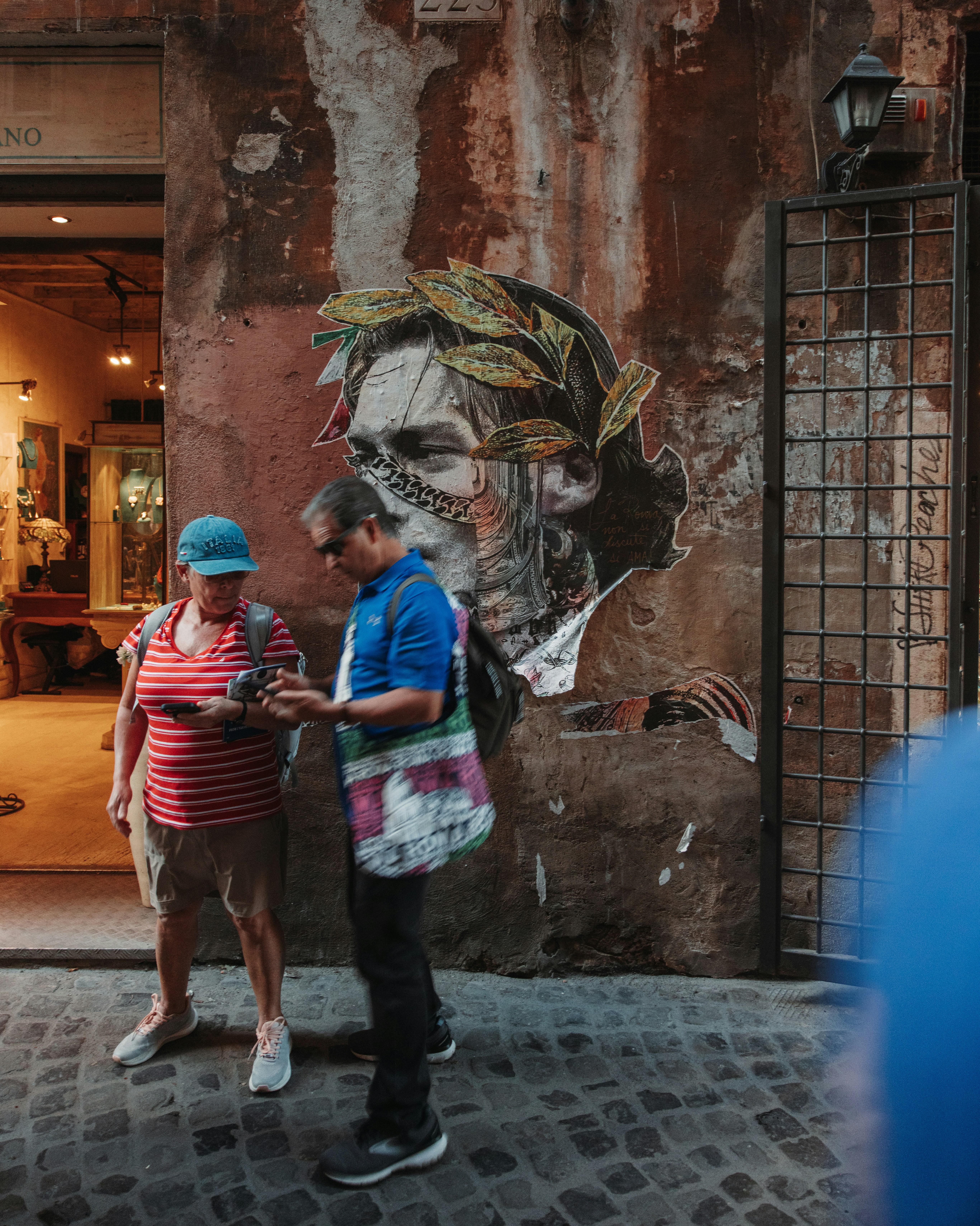 Laurel-Crowned Portrait on a Weathered Wall Anchors a Street Moment
