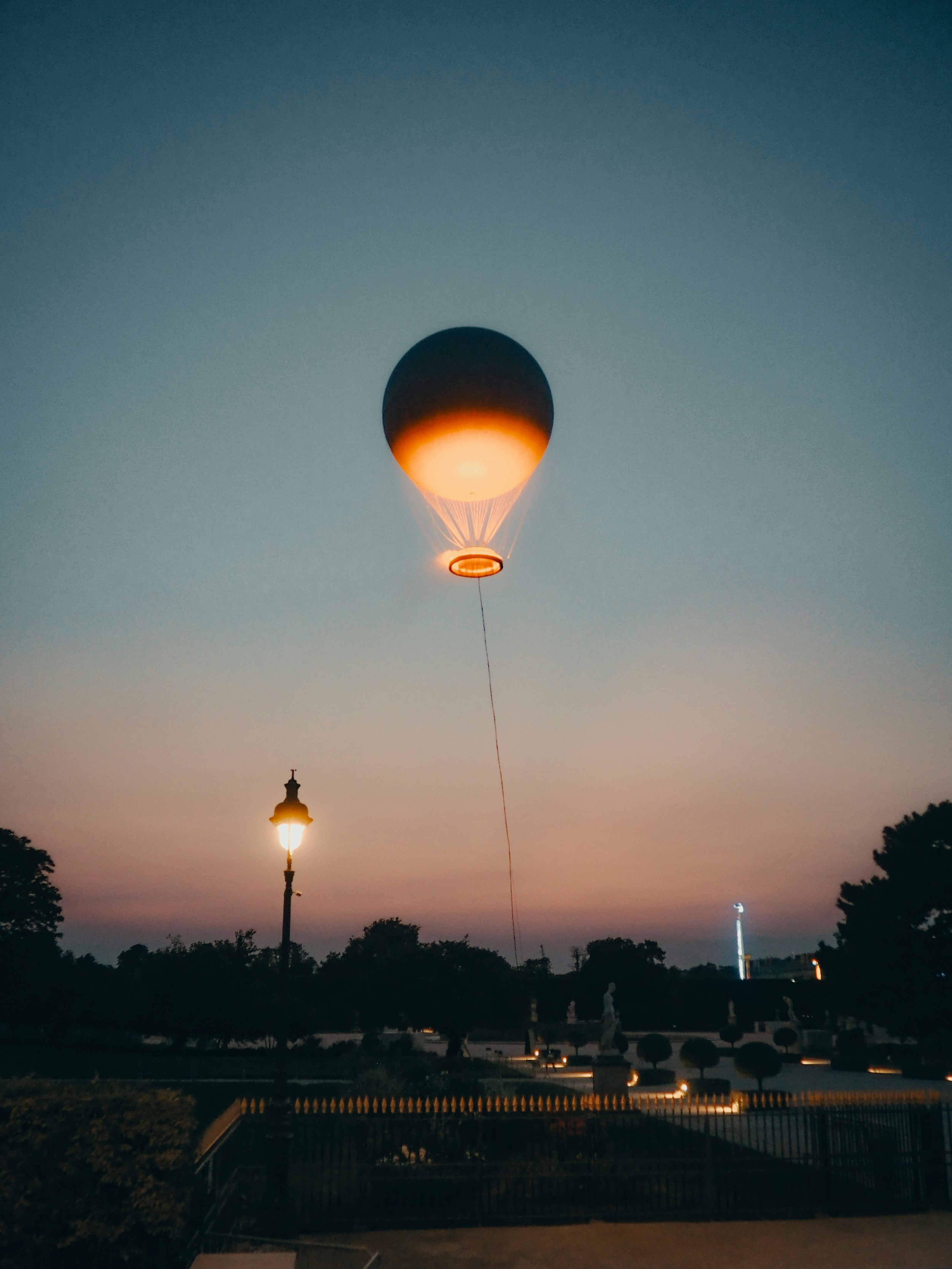 Hot air balloon glows at dusk over park landscape. photo – Free Night ...