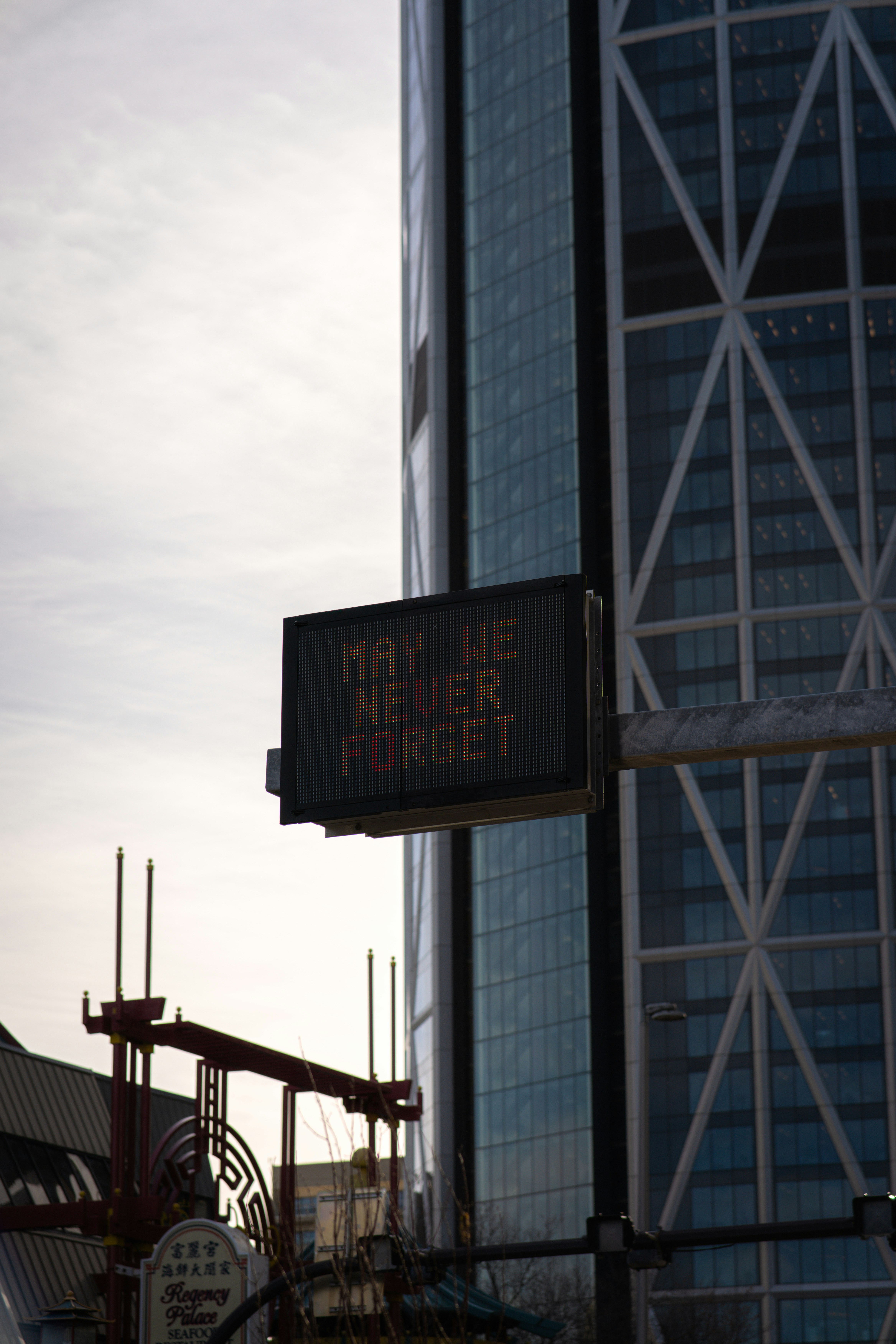 May We Never Forget: Neon Ledger Against a Glass Skyline