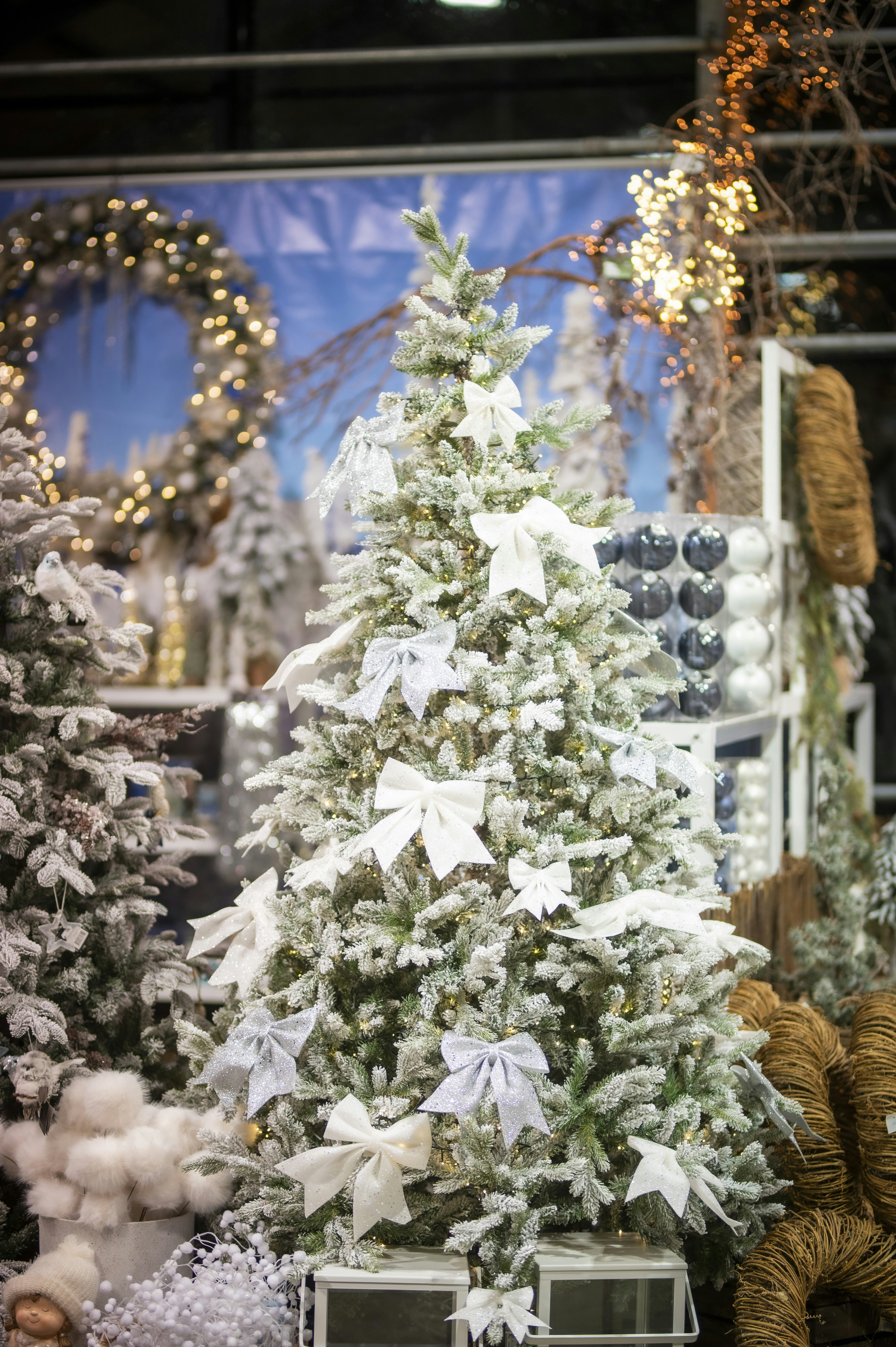 Snow-Dusted Ivory Bows: A Christmas Tree Centerpiece in a Cozy Holiday Shop