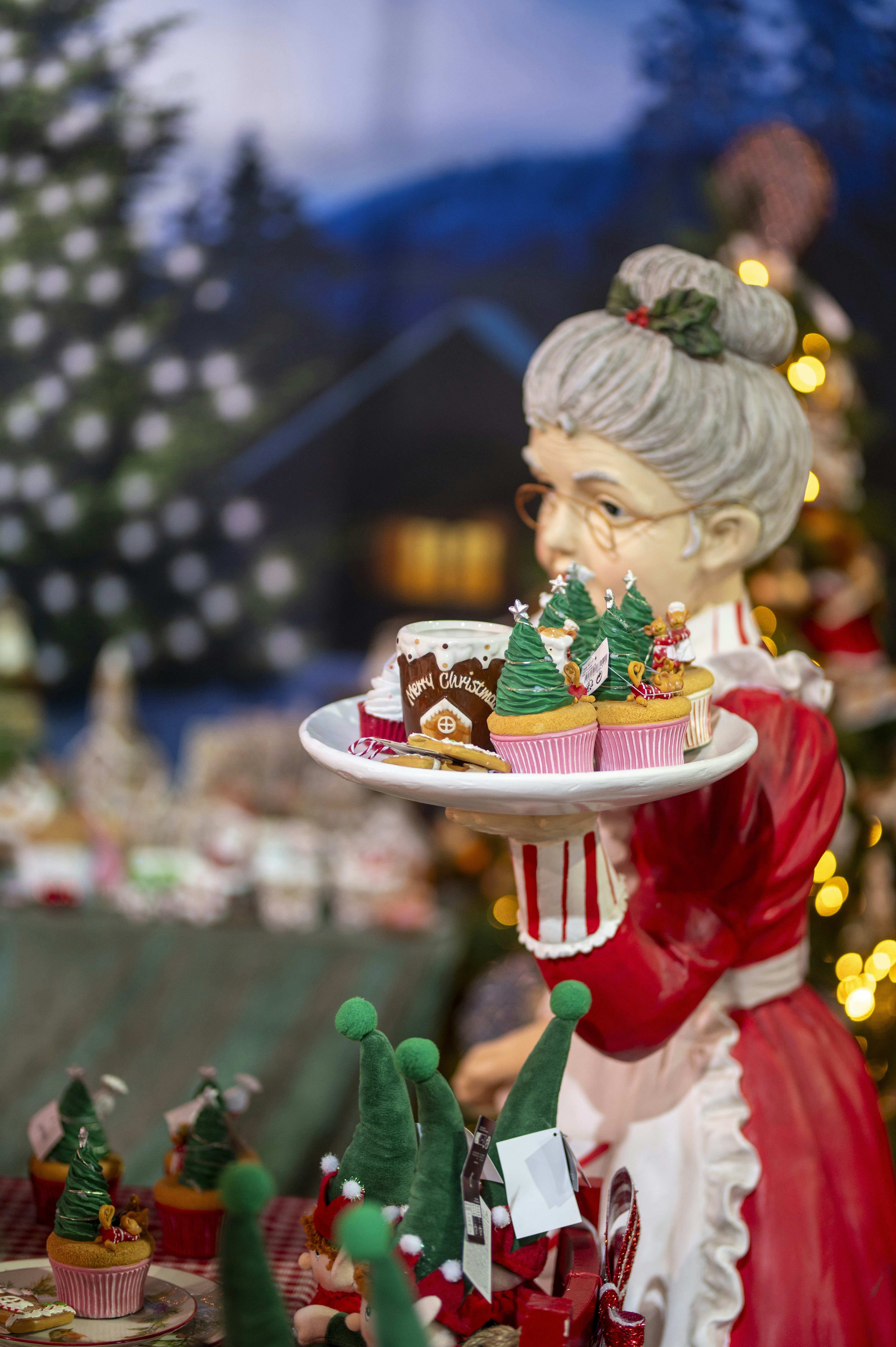 Mrs. claus holding a tray of festive cupcakes