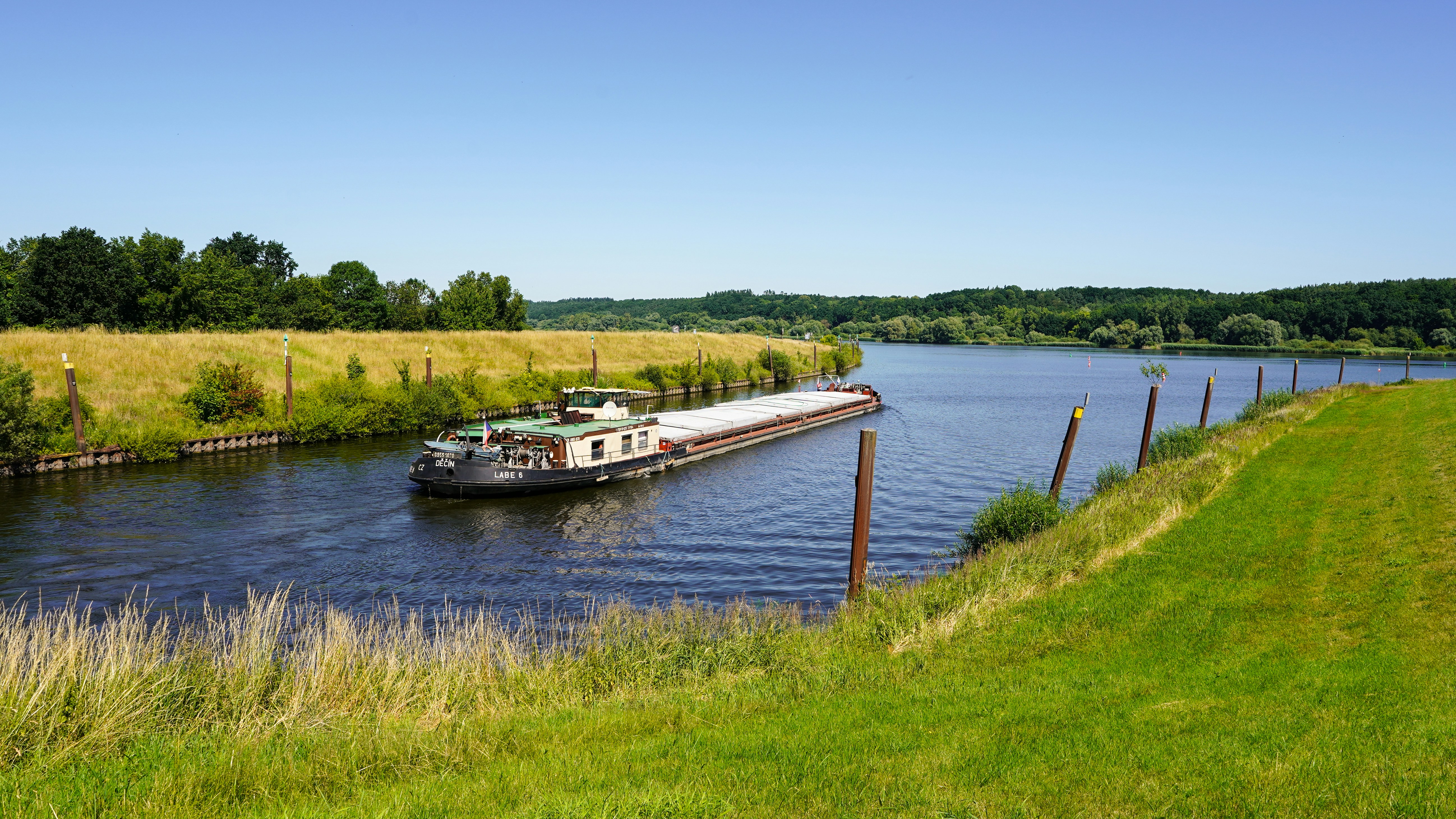 Towboat on a Quiet Canal Between Golden Fields and a Clear Sky