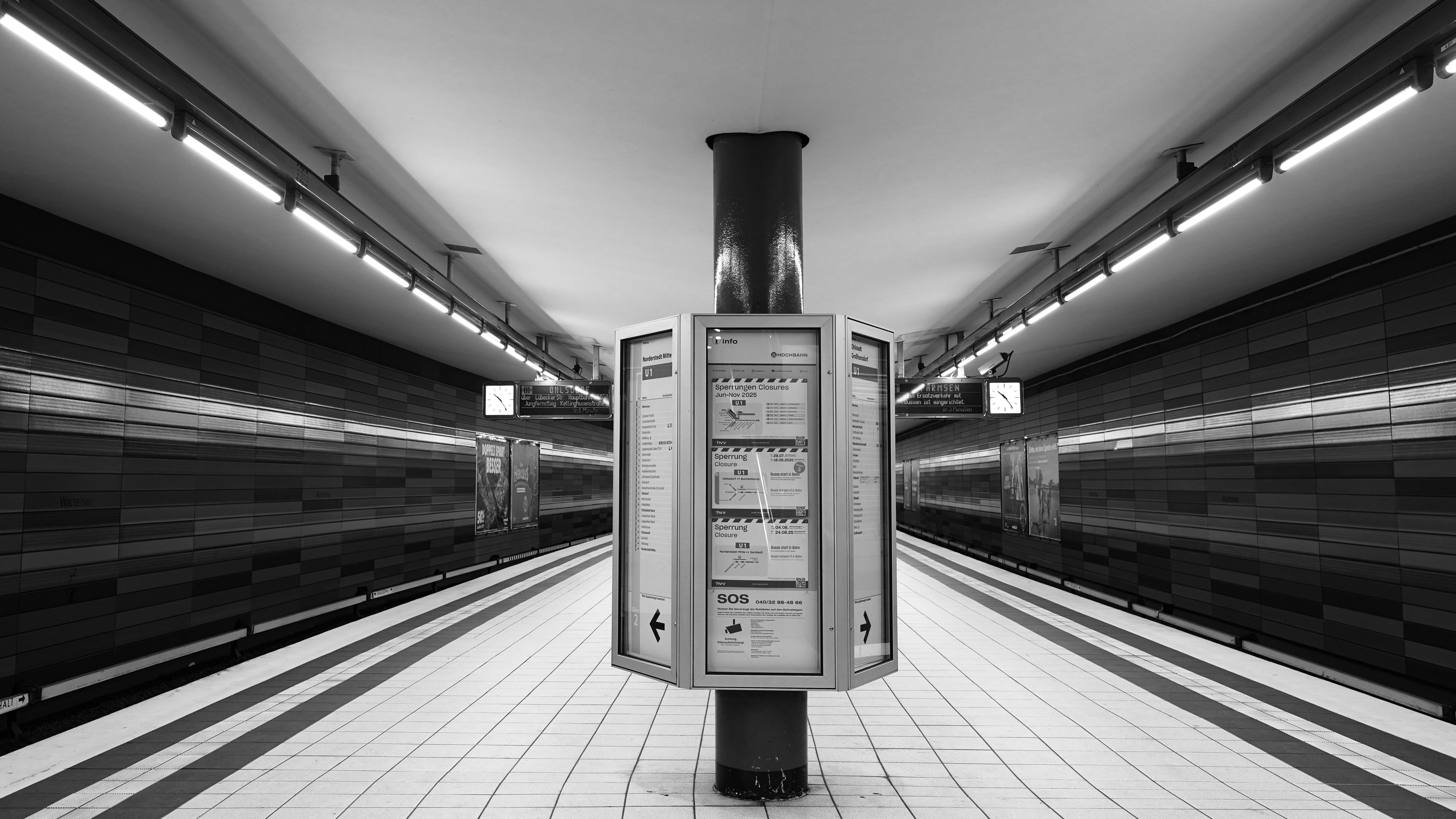 Centered Concourse: The Subway Information Kiosk Anchors a Monochrome Tunnel
