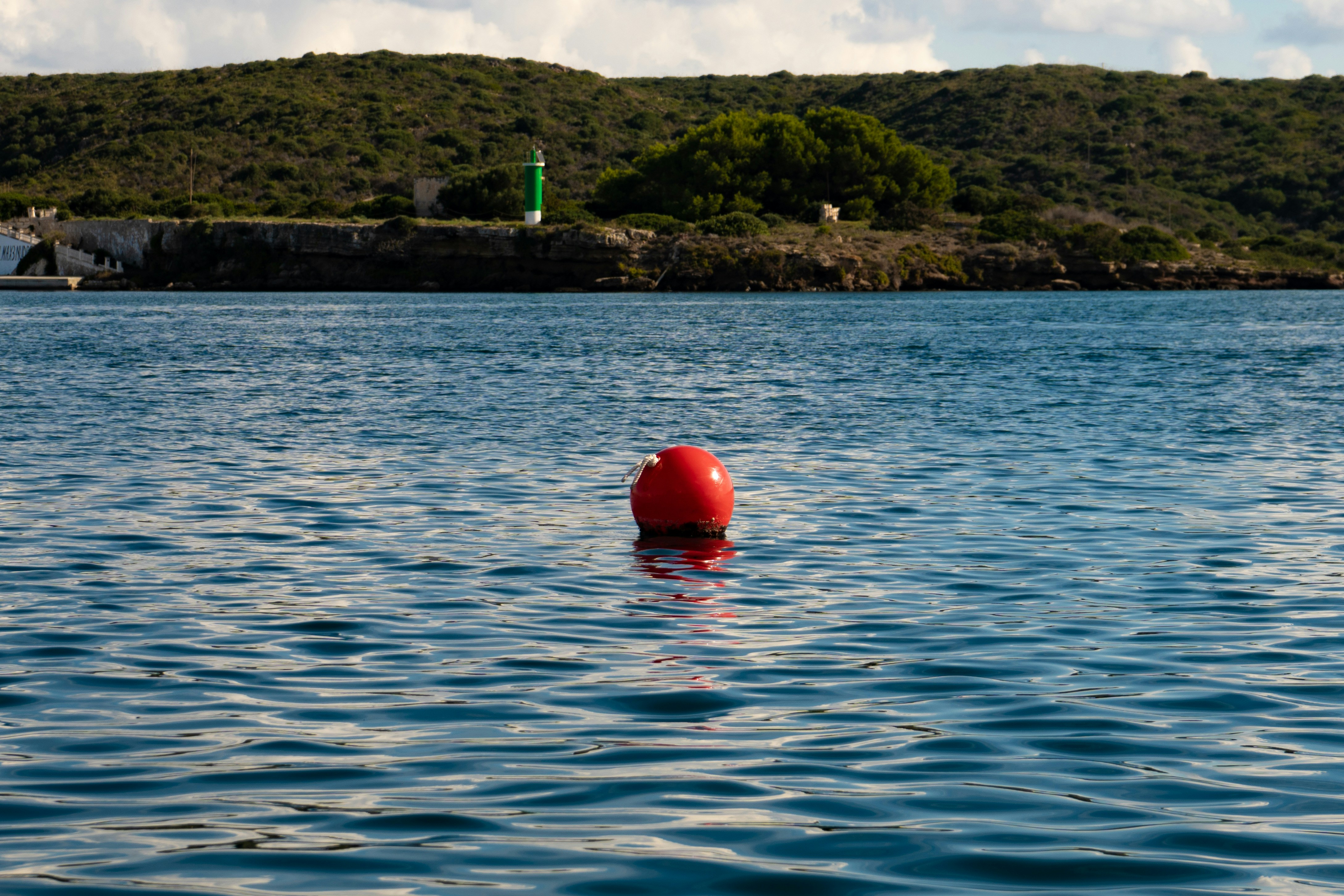 Red Buoy on Quiet Blue: A Beacon Across Rippled Water
