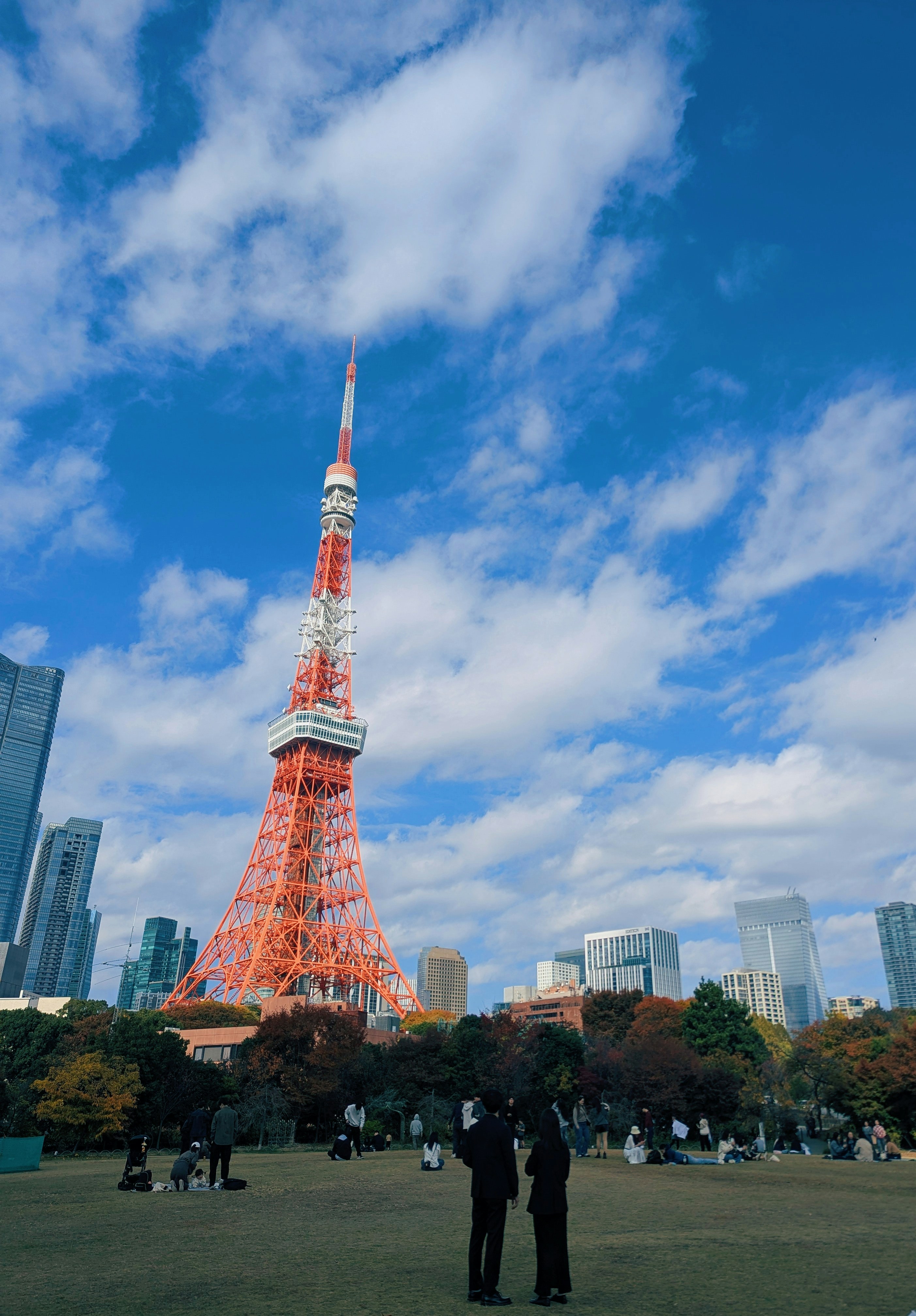 Crimson lattice of Tokyo Tower rises above a sunlit park