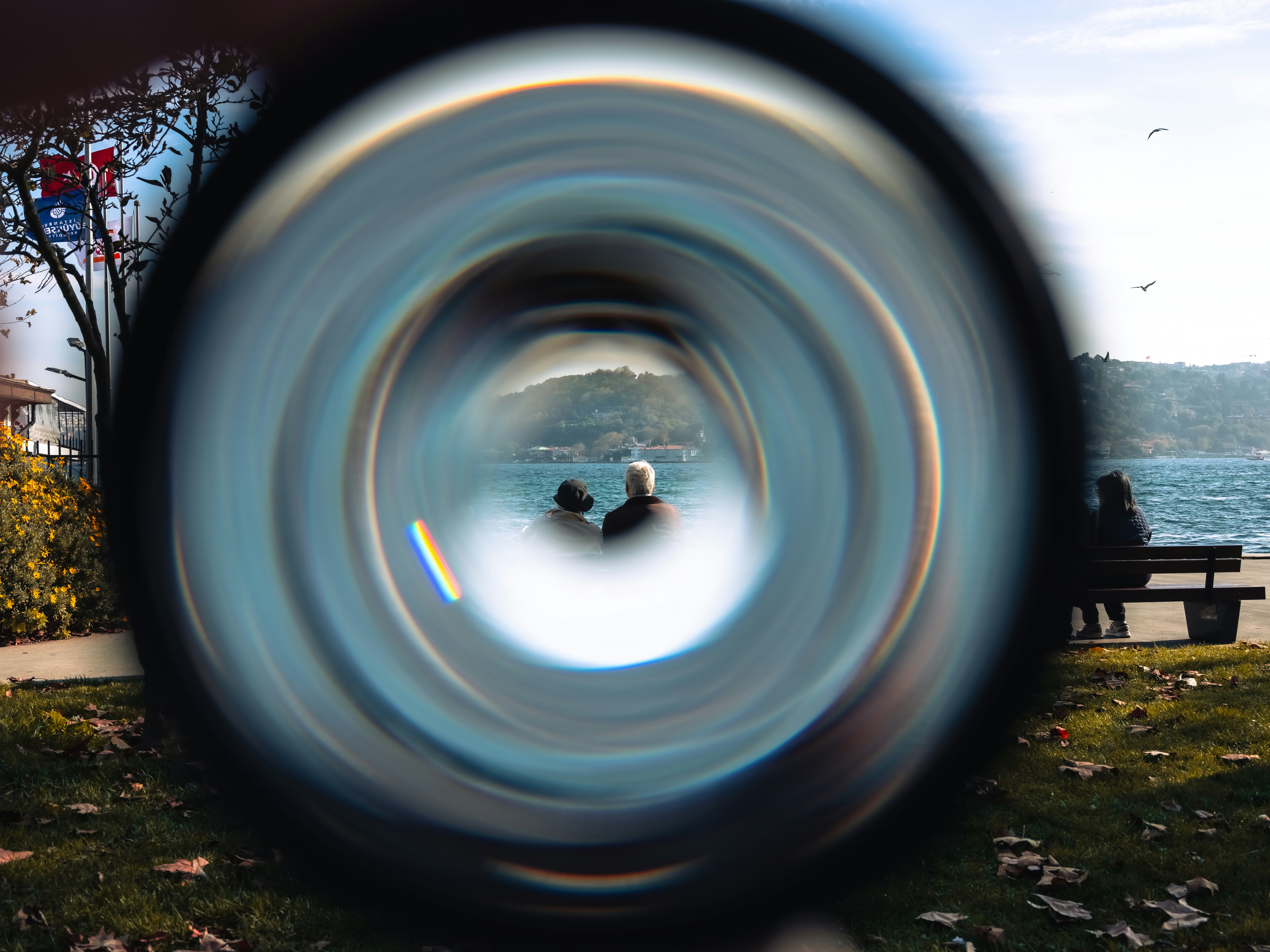 Circular Frame at the Lakeside: Two Figures on a Bench Through a Close-Up Lens