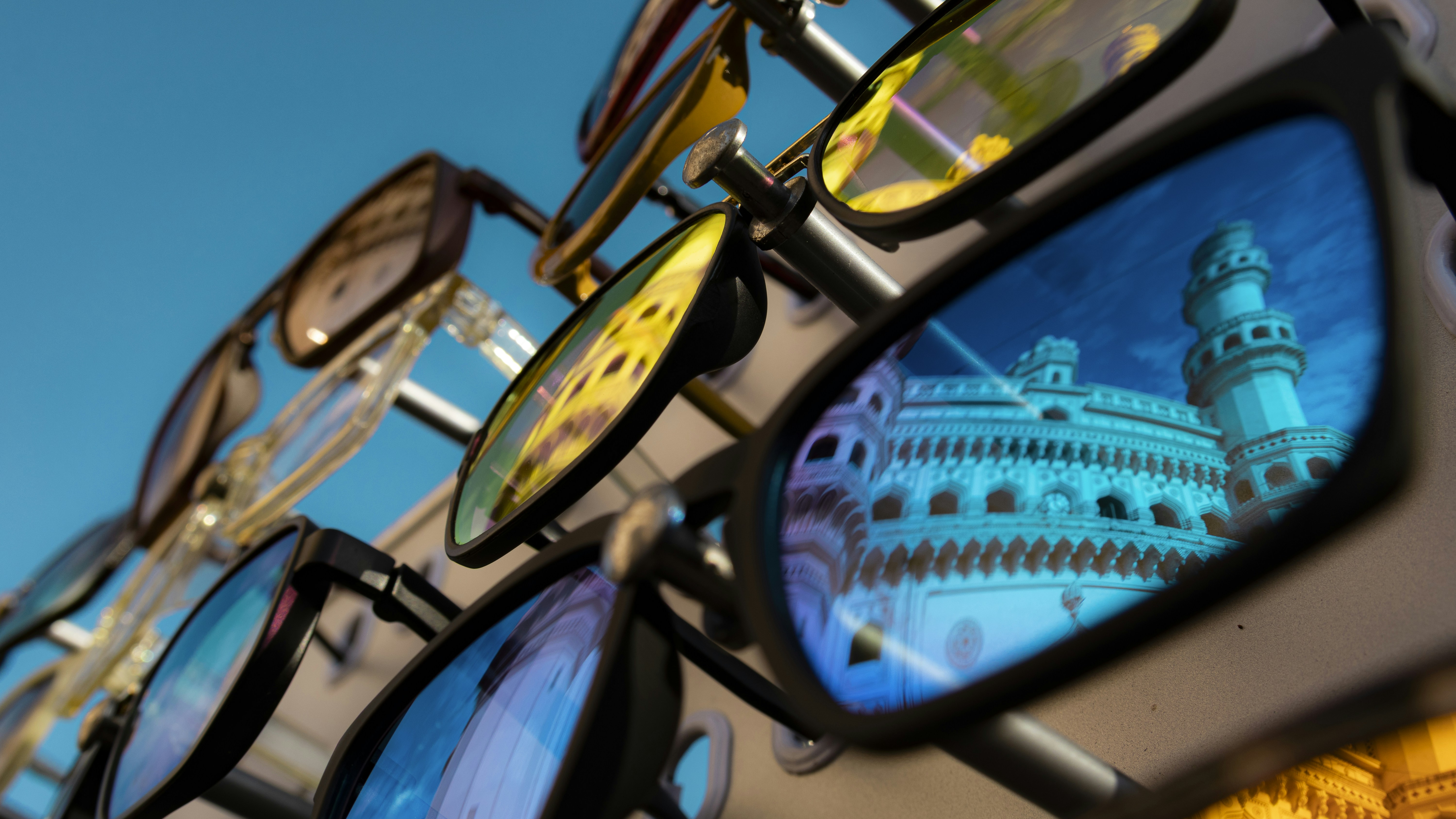Row of Reflections: Sunglasses Parading Sky and a Towered Facade