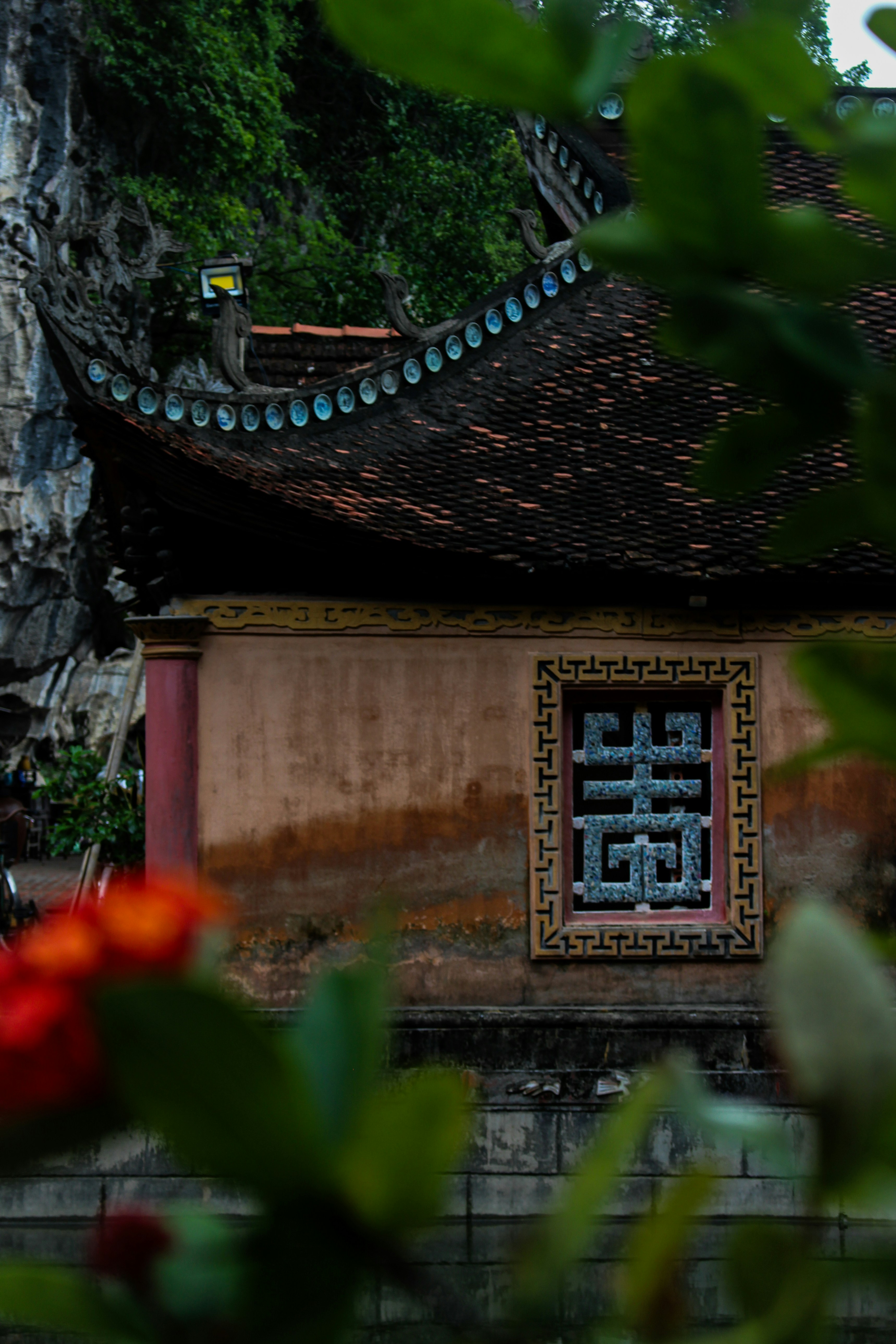 Blue Geometric Window on a Weathered Temple Wall Framed by Foliage