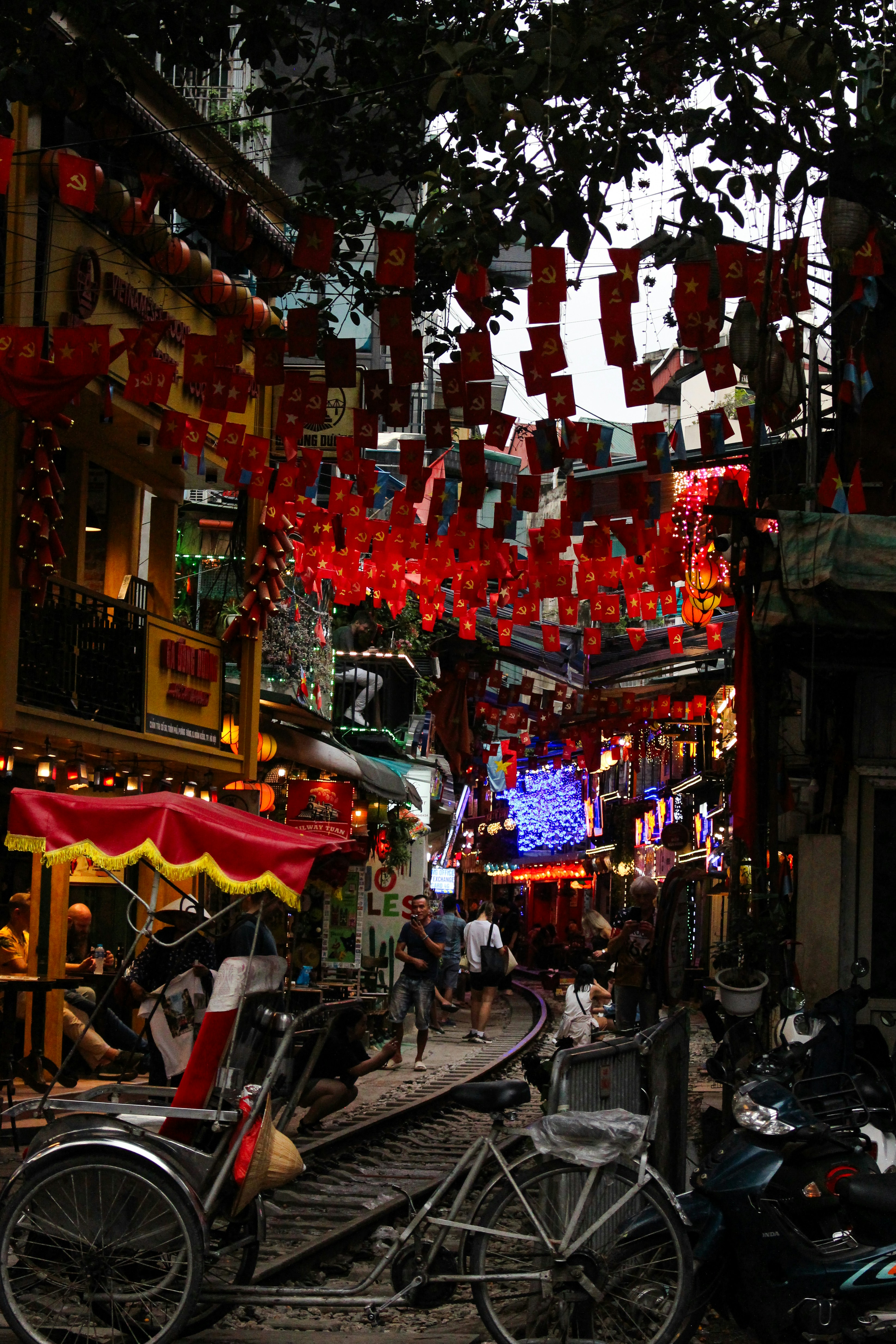 Flag-Laced Night Market: Neon Alleys, Bicycles, and Cobblestones
