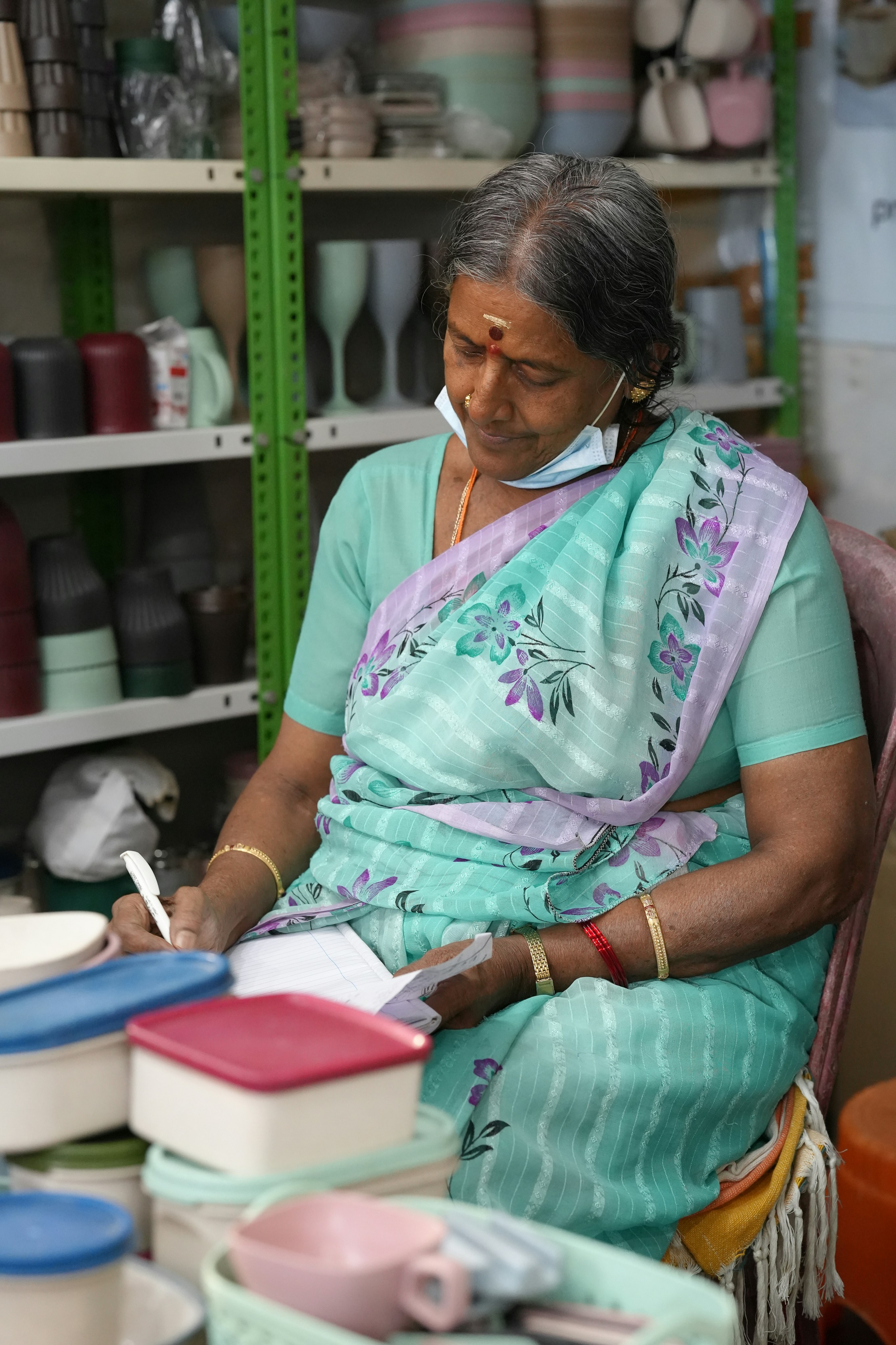 Sari-Clad Shopkeeper Scribes Amid a Sea of Jars