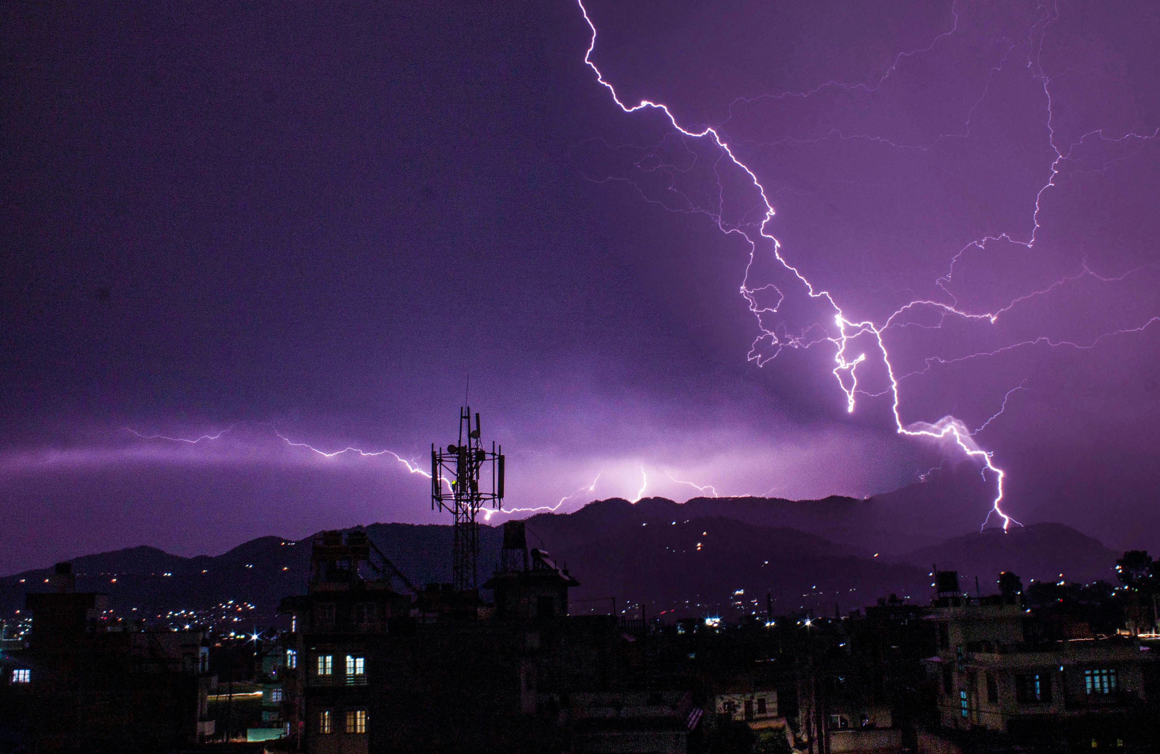 Purple Nightfire Over Rooftops: Lightning Splinters Across the City