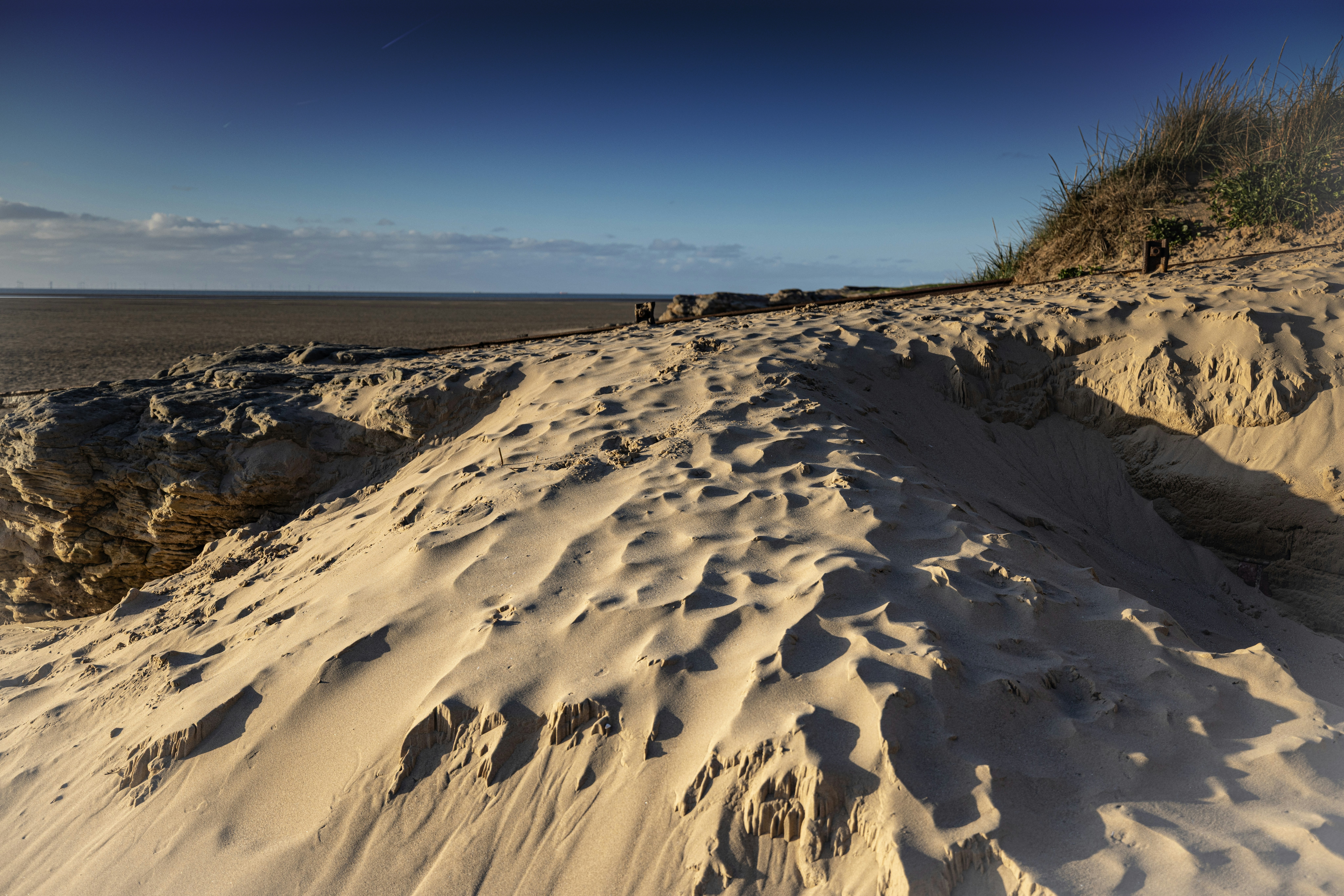 Footprints Toward the Quiet Sea: Wind-Sculpted Dune under a Blue Sky