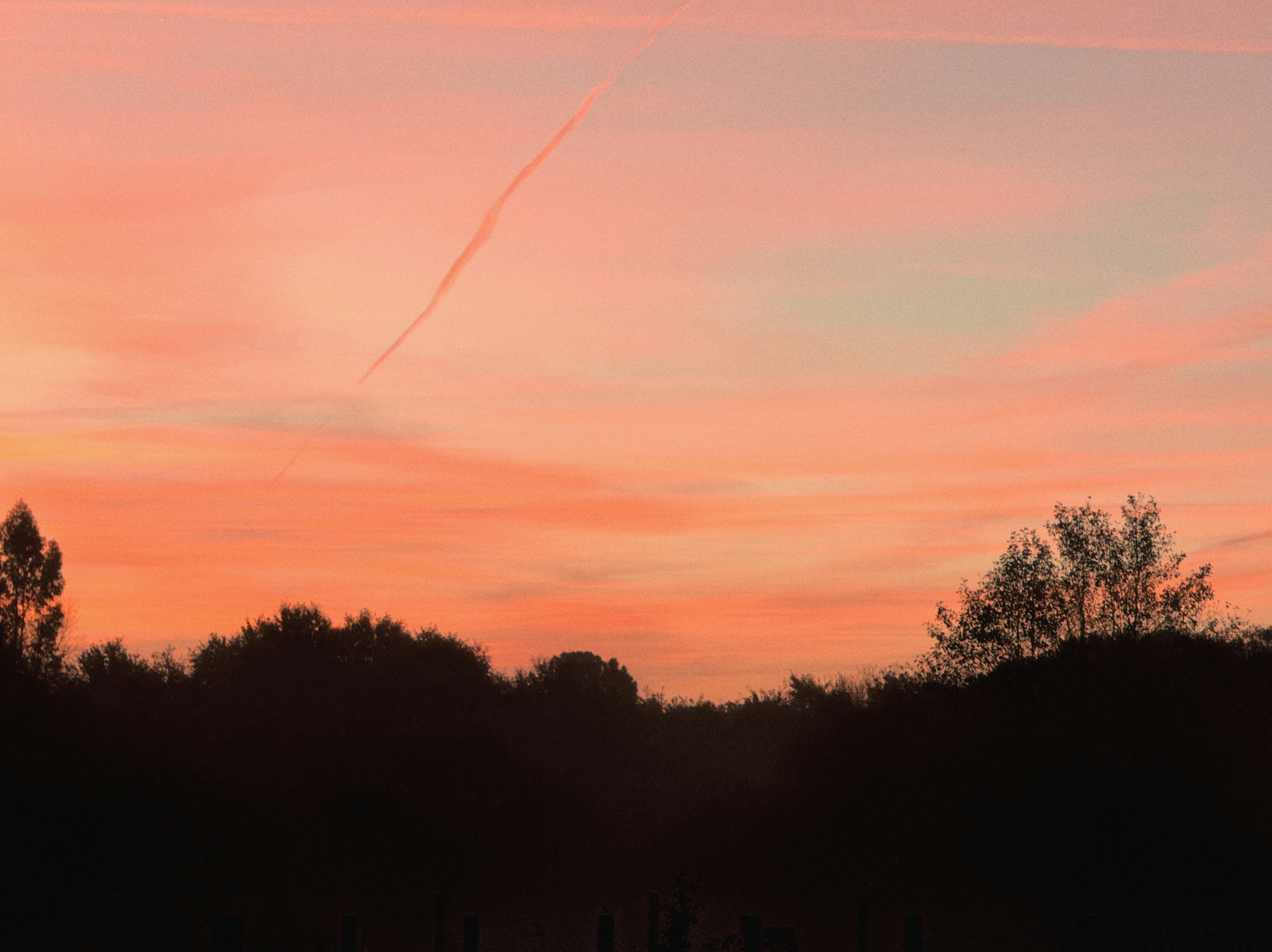 Diagonal Contrail Across a Coral Sunset