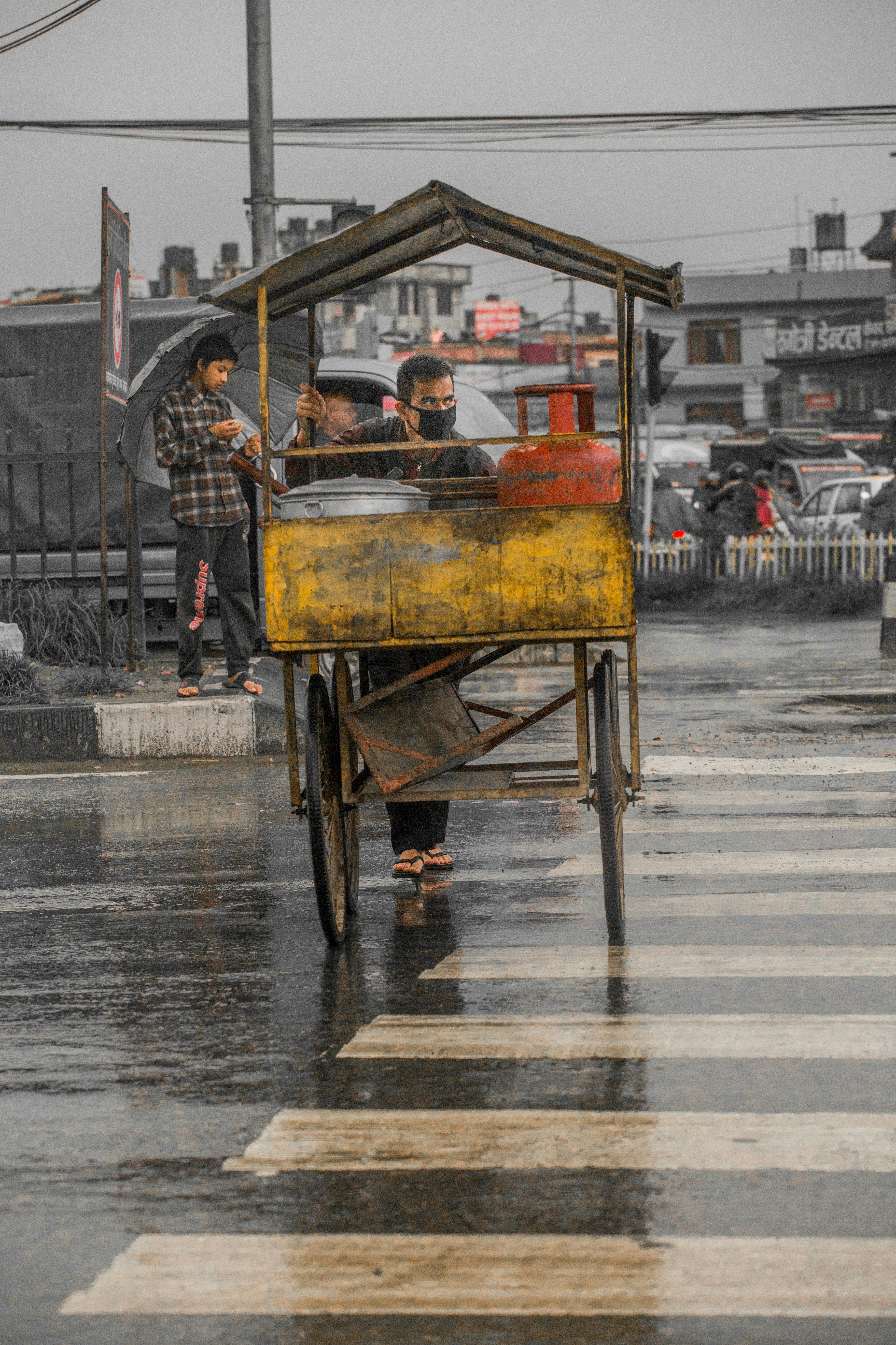 Rain-Slick Street Cart Portrait: A Masked Vendor at a Yellow Cart in a Grey City