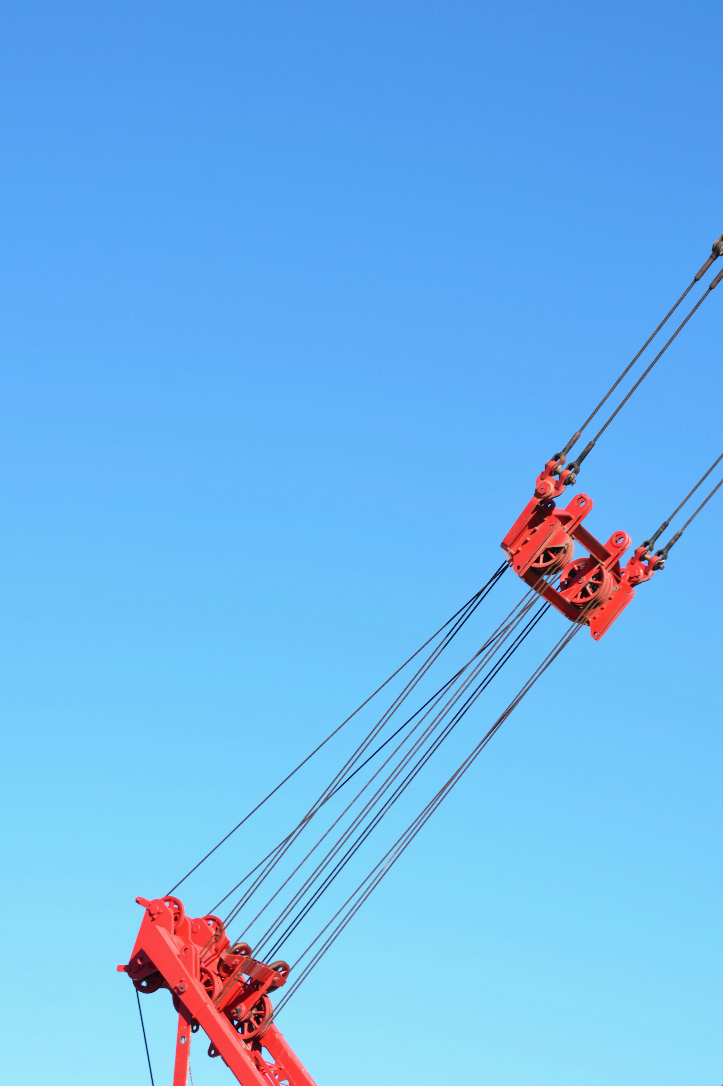 Crimson Tension: Red Cable Rig Cutting Across a Clear Blue Sky