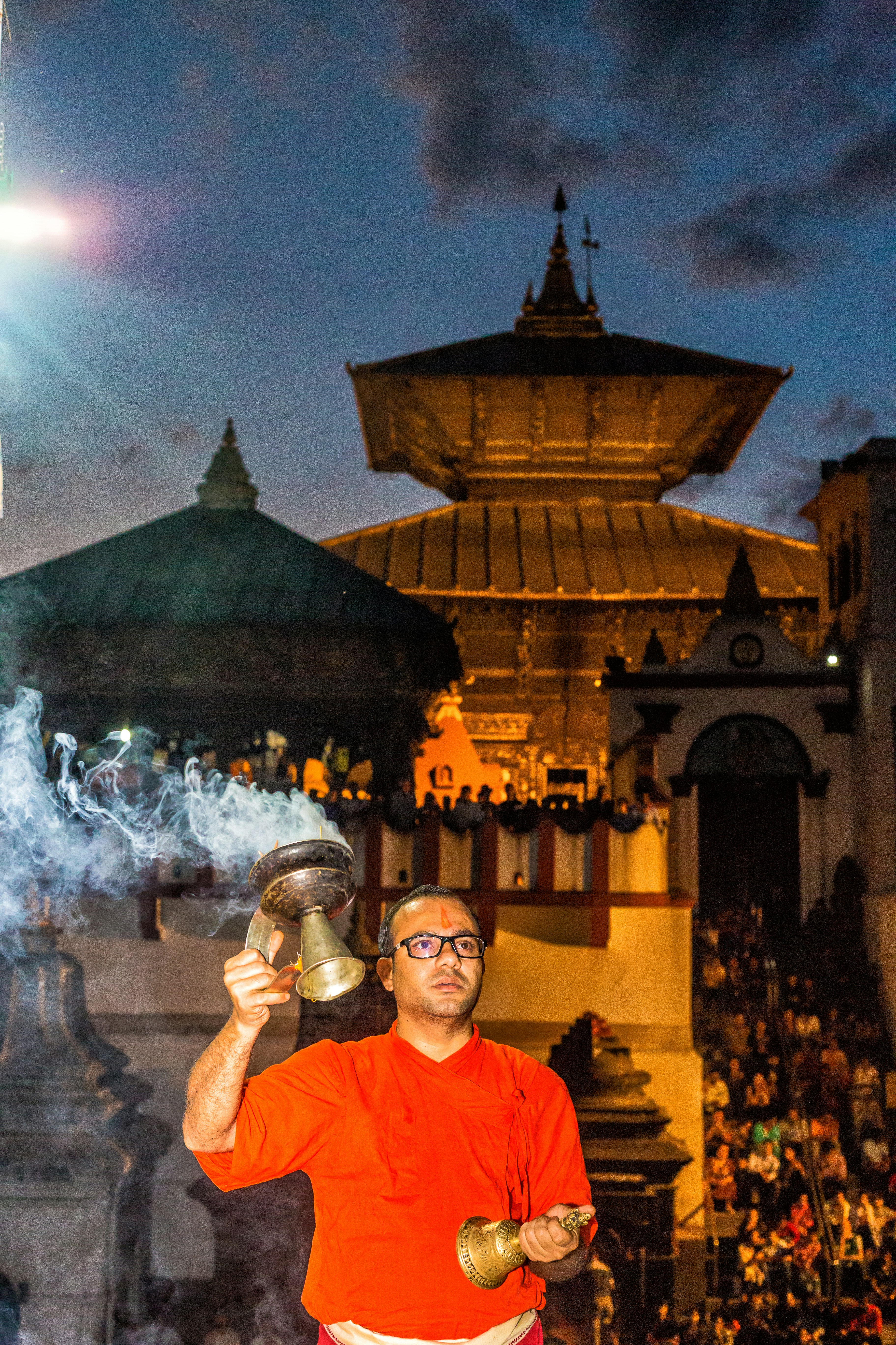 Orange-clad Bell Ringer at a Golden Temple Night Ceremony
