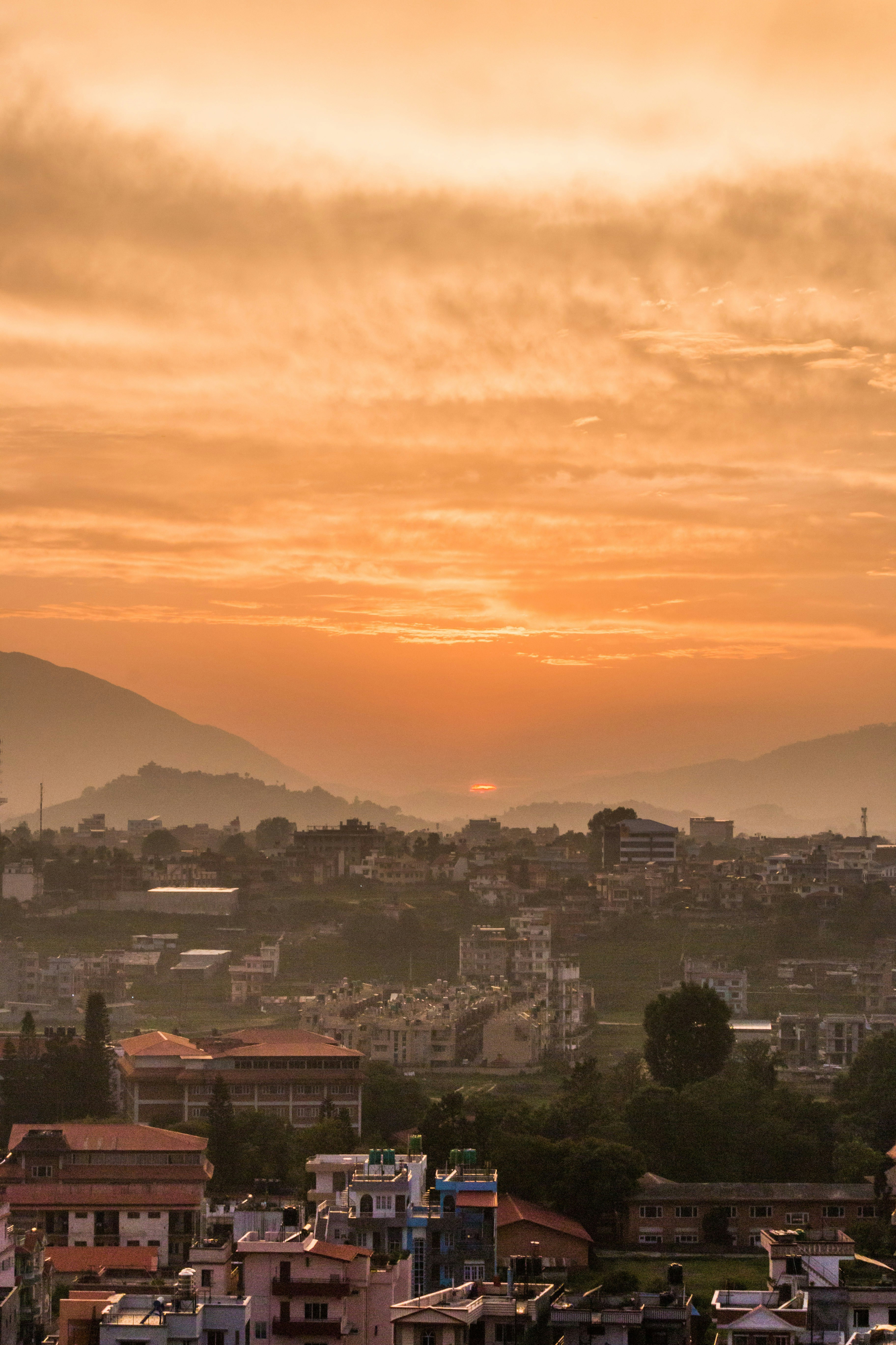 Crimson Dusk Over the Valley City: Sunlit Silhouettes and Misty Hills