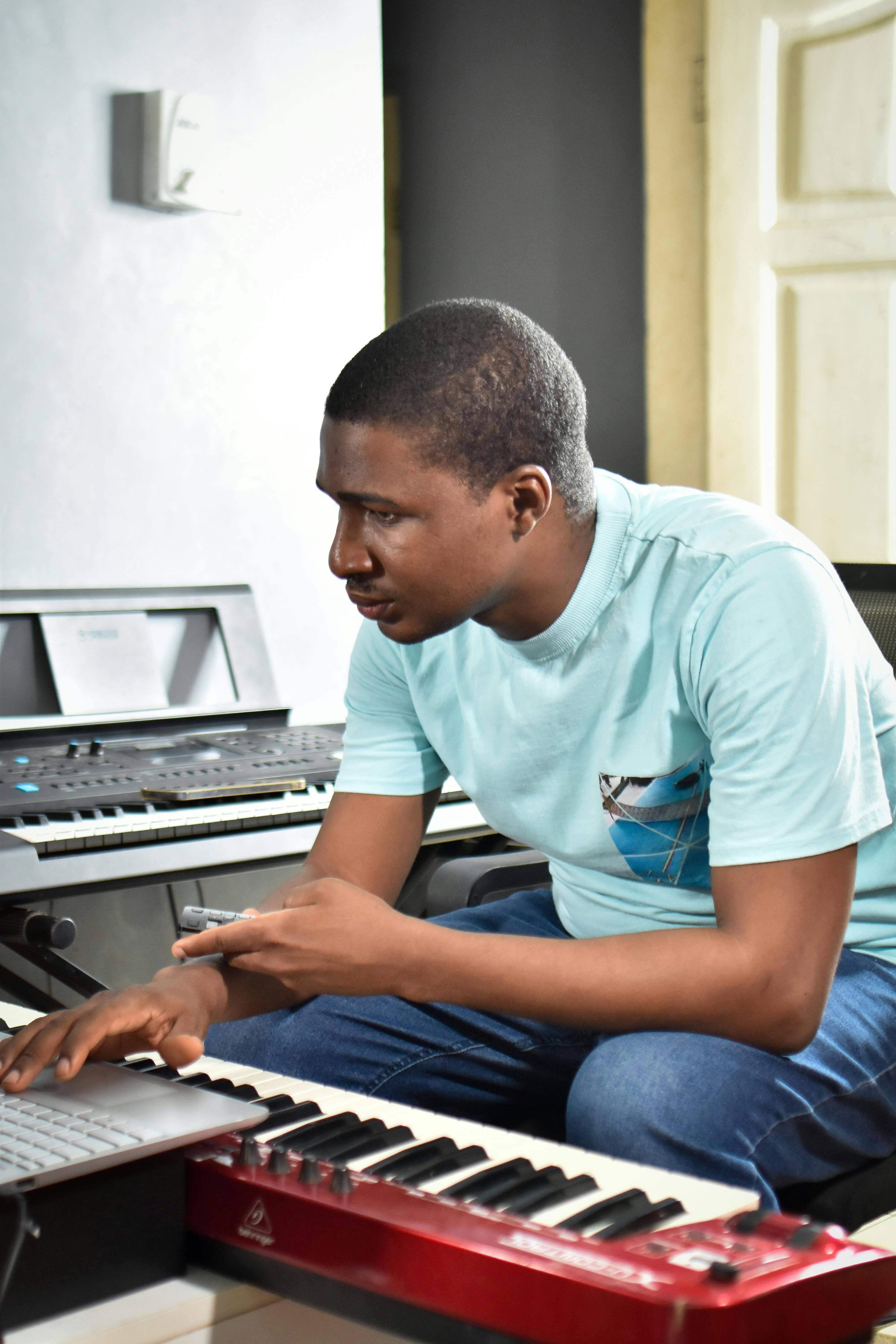A music producer in a music production session with two keyboards and a laptop computer