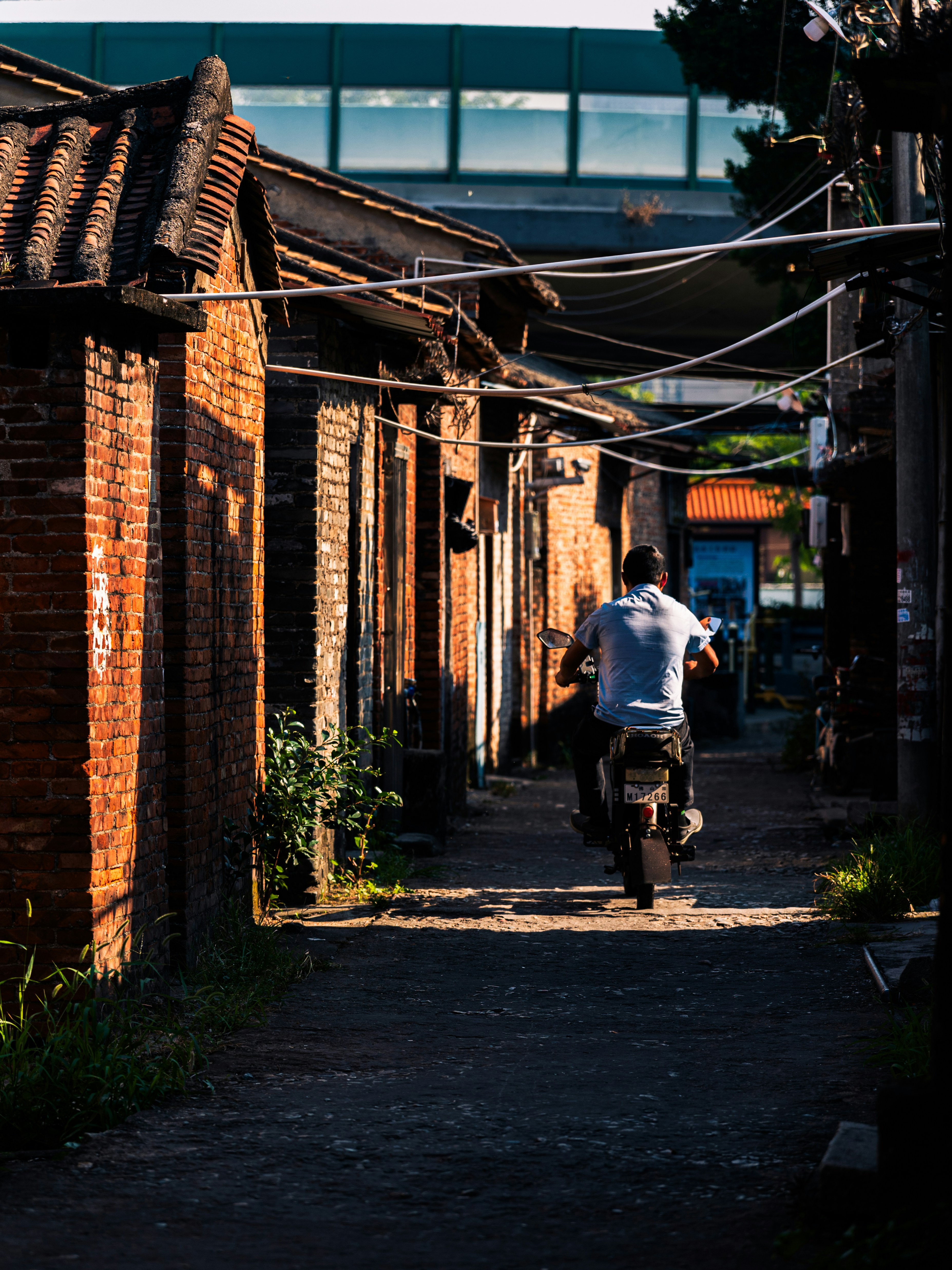 Rider in a Sunlit Brick Alley: A Quiet Urban Passage