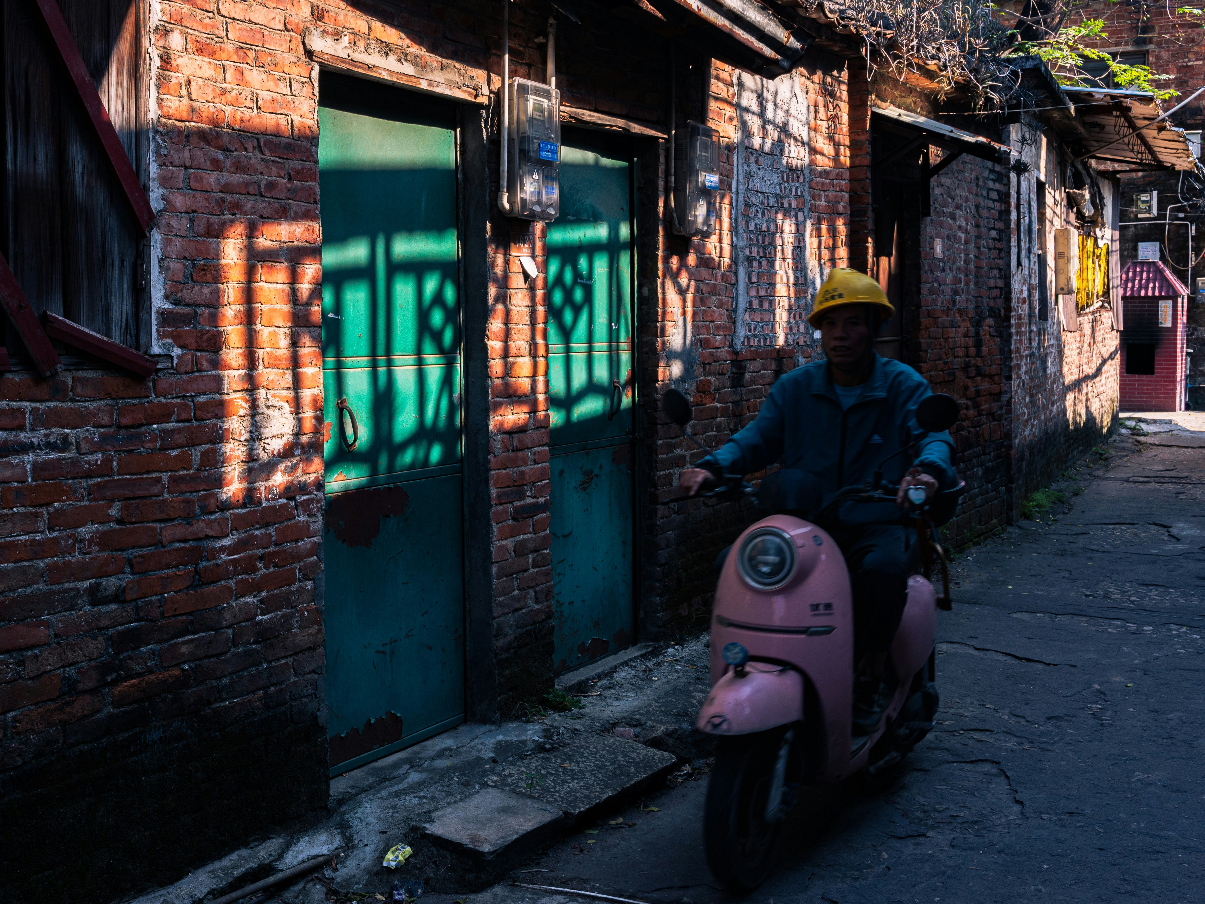 Pastel Pink Scooter Amid Narrow Brick-Alley Shadows