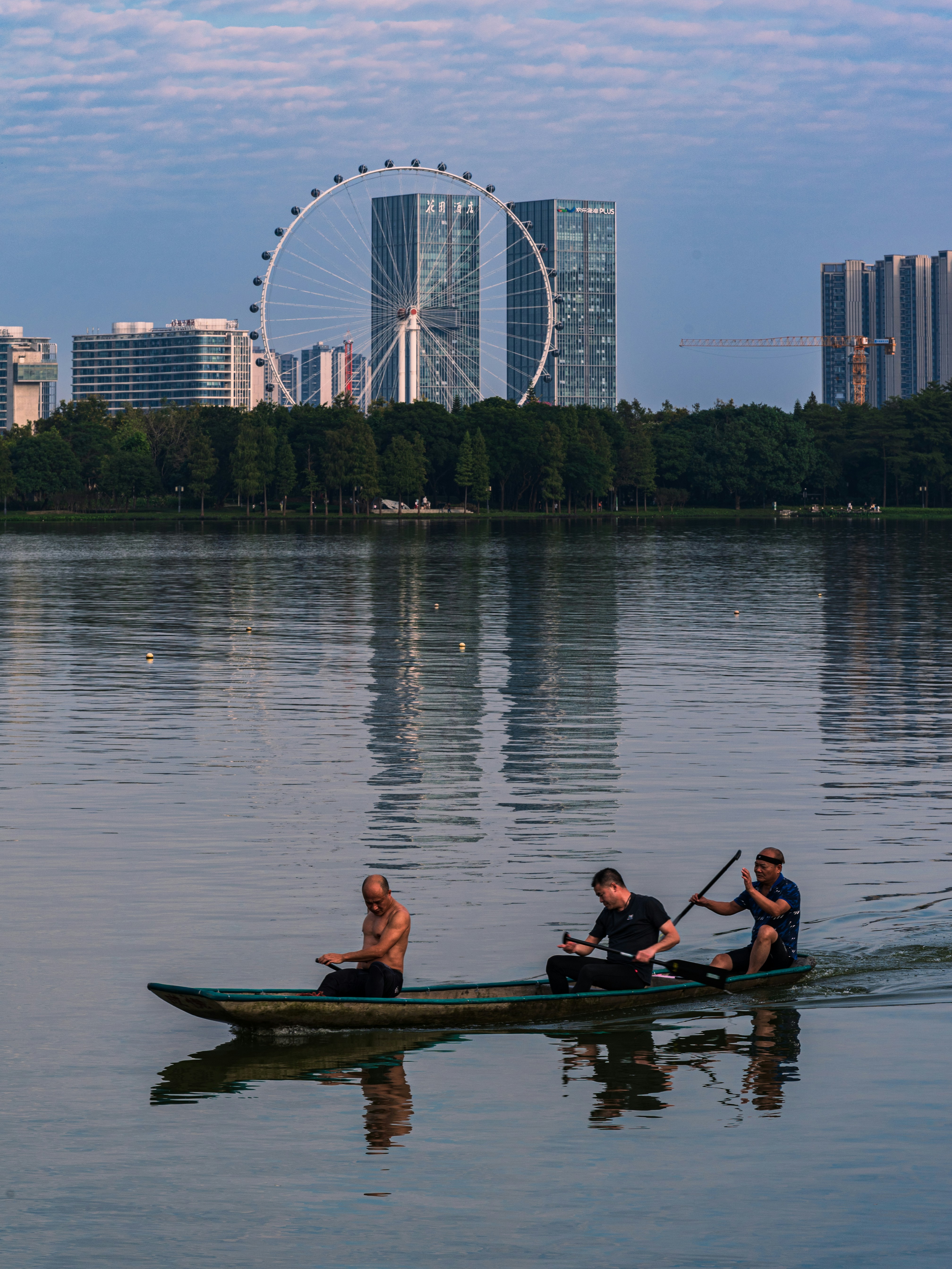 Rowers and Reflections: A Canoe Beneath the Ferris Wheel