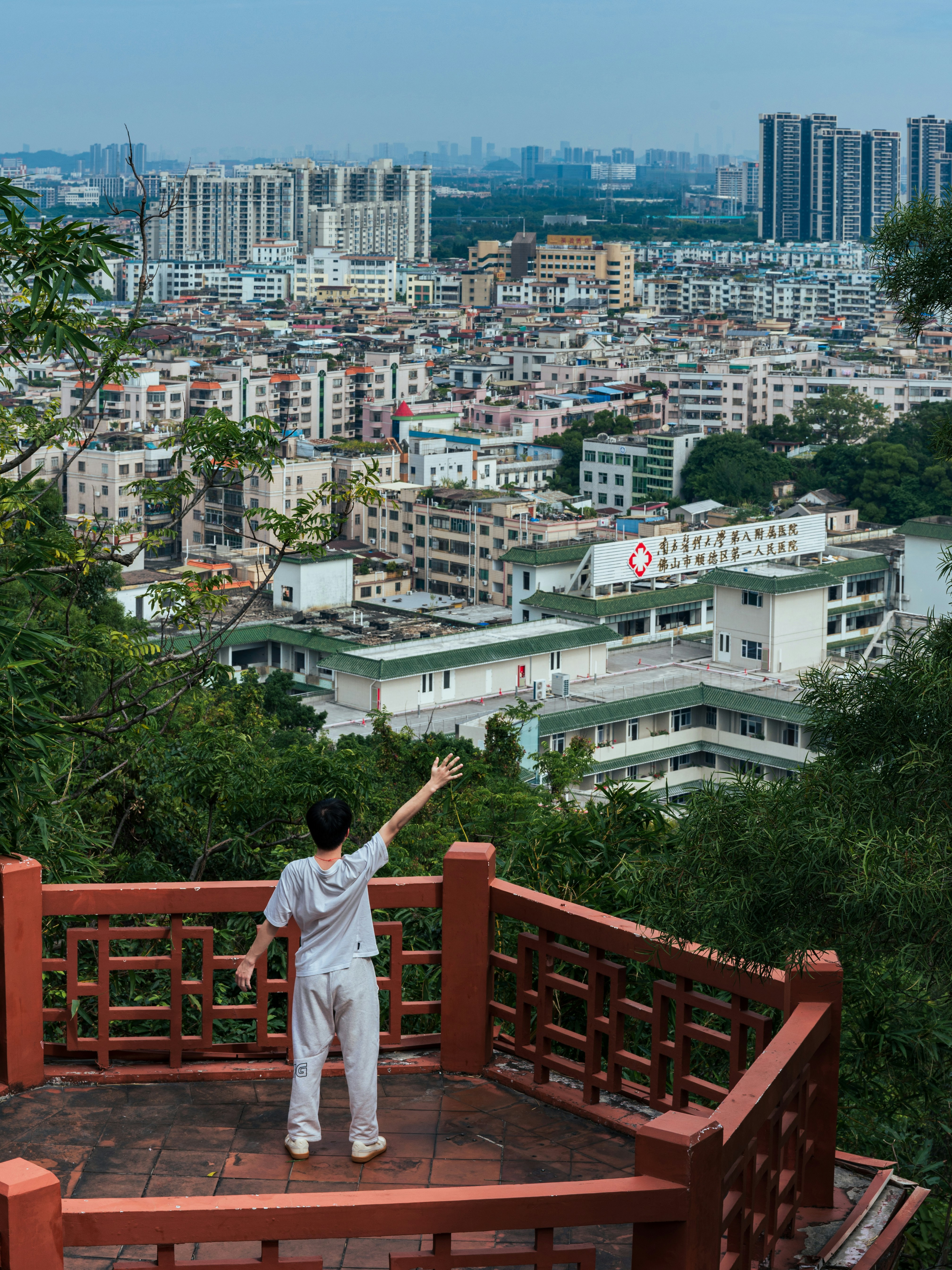 Gesture at the Edge: A Cityscape Framed by a Red Balcony