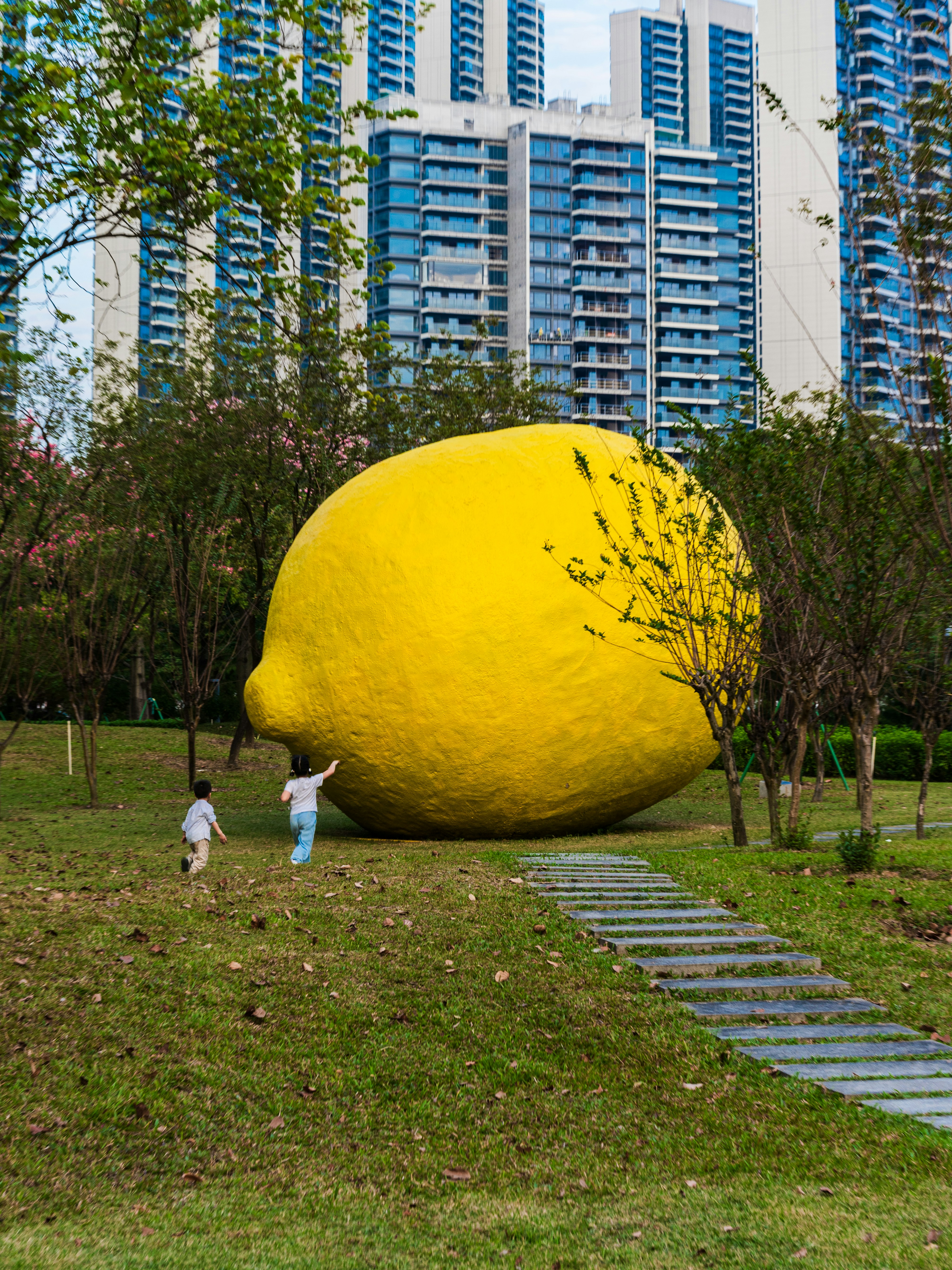 Sunlit Citrus Monument: A Giant Yellow Sculpture Anchoring a City Park