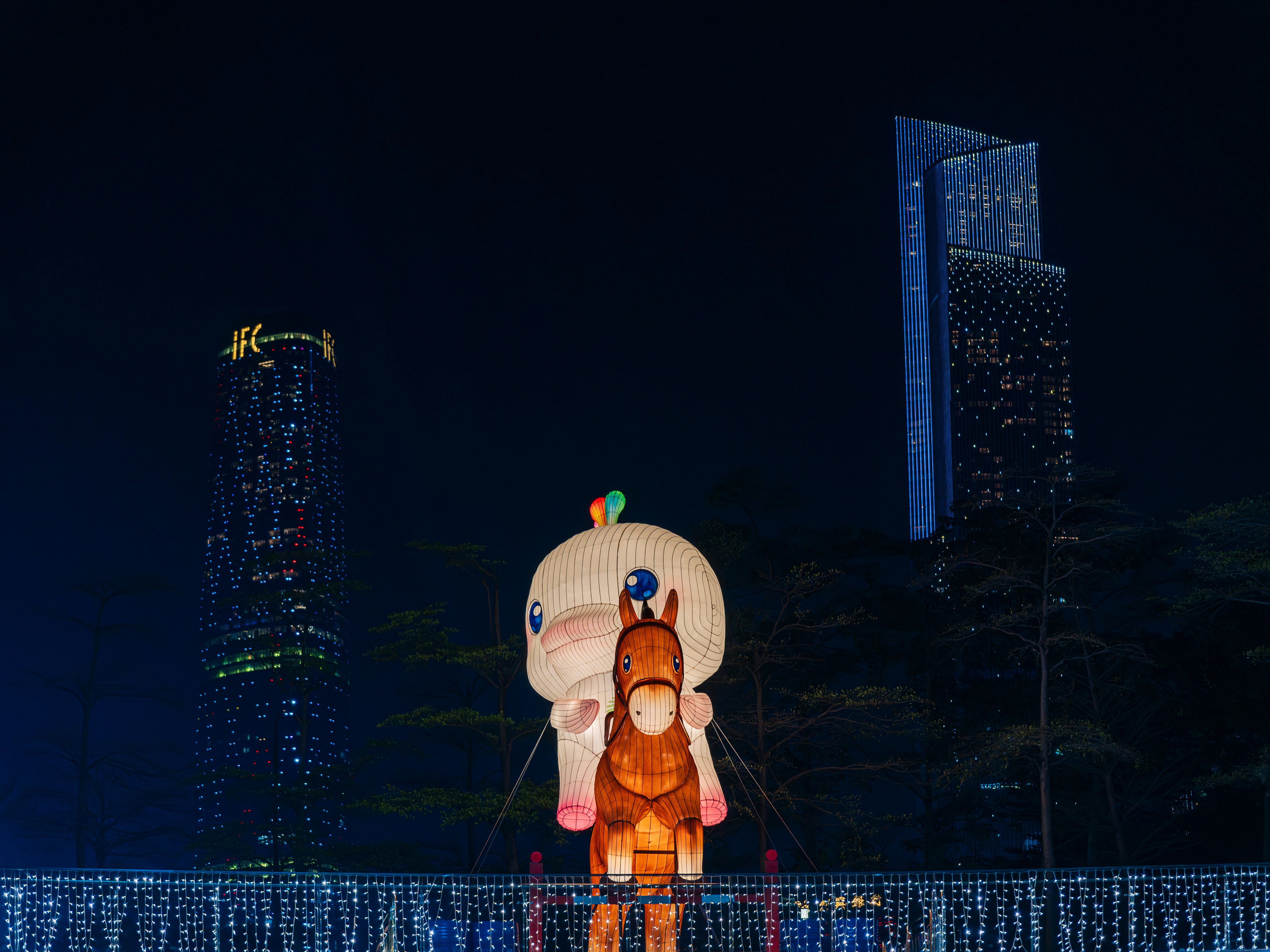 Neon Sentinel: A Giant Inflatable Cartoon Figure Over a Nighttime Cityscape