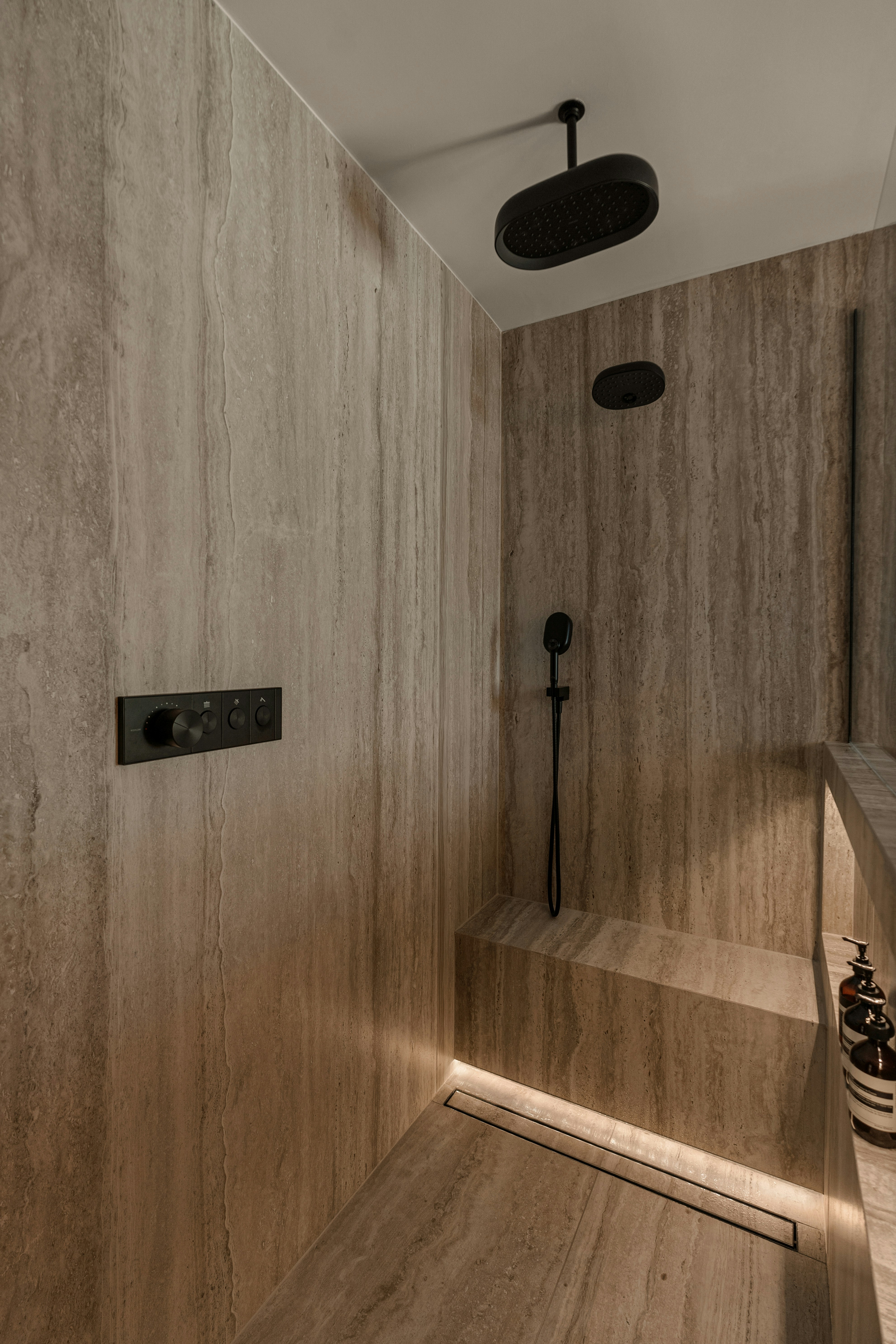 Luxury bathroom renovation with a stone vanity, floating cabinets, and walk-in shower. Soft ambient lighting and modern design create a high-end, minimalist aesthetic.