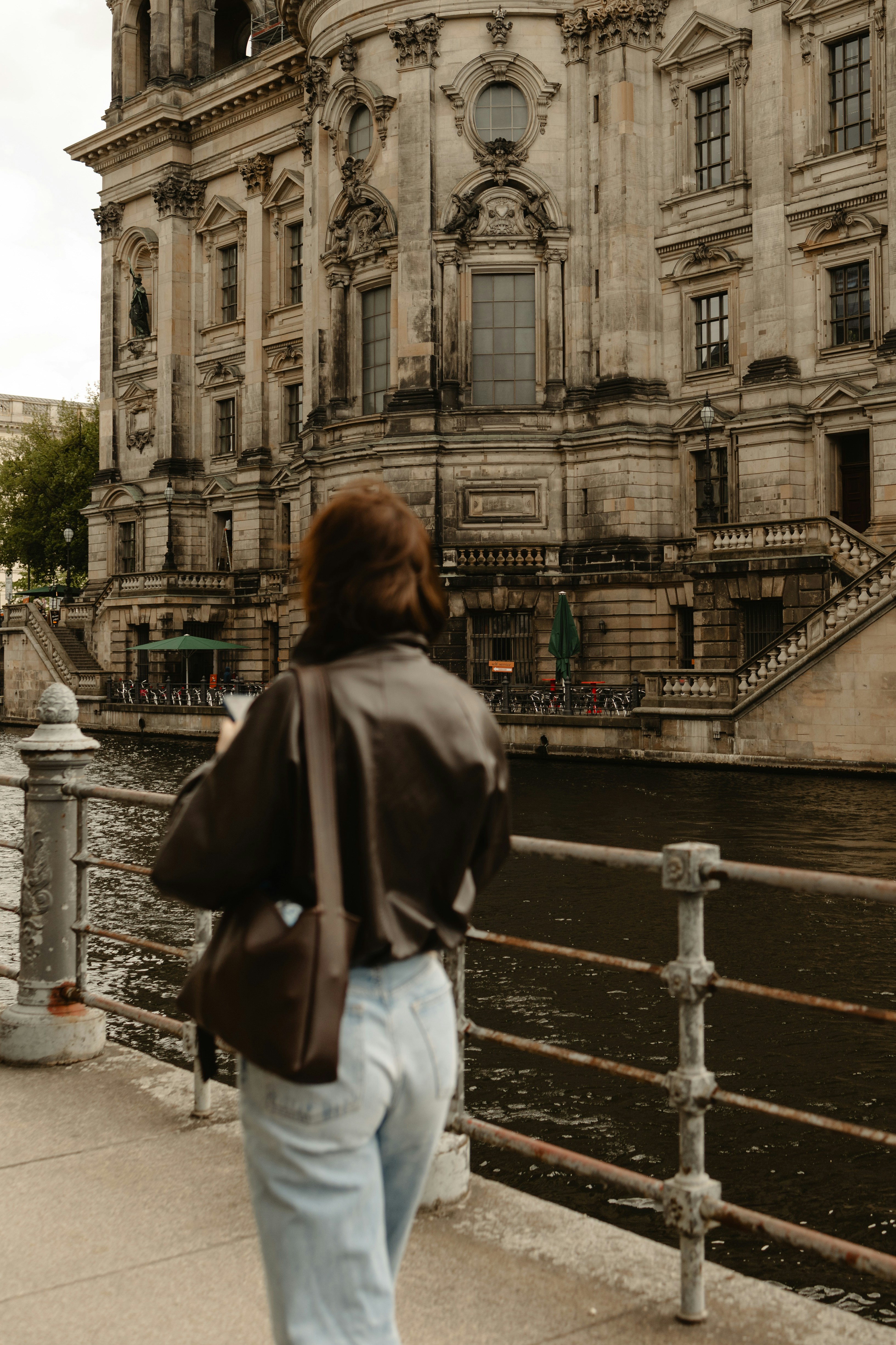 Back to the City: A Wanderer Framed by an Ornate Riverside Façade