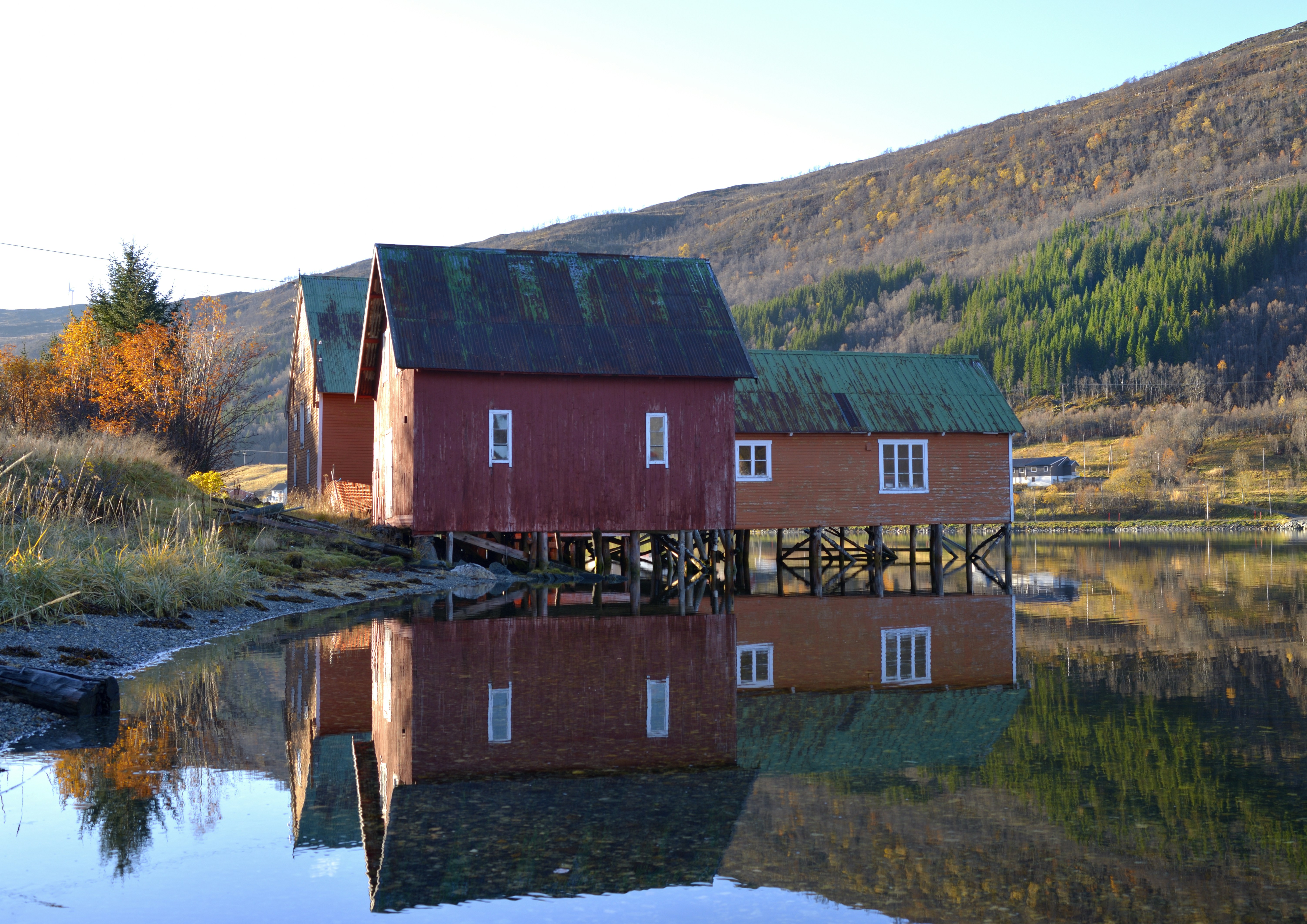 Red Boathouses on Stilts Reflect Autumn Light Across a Tranquil Lake