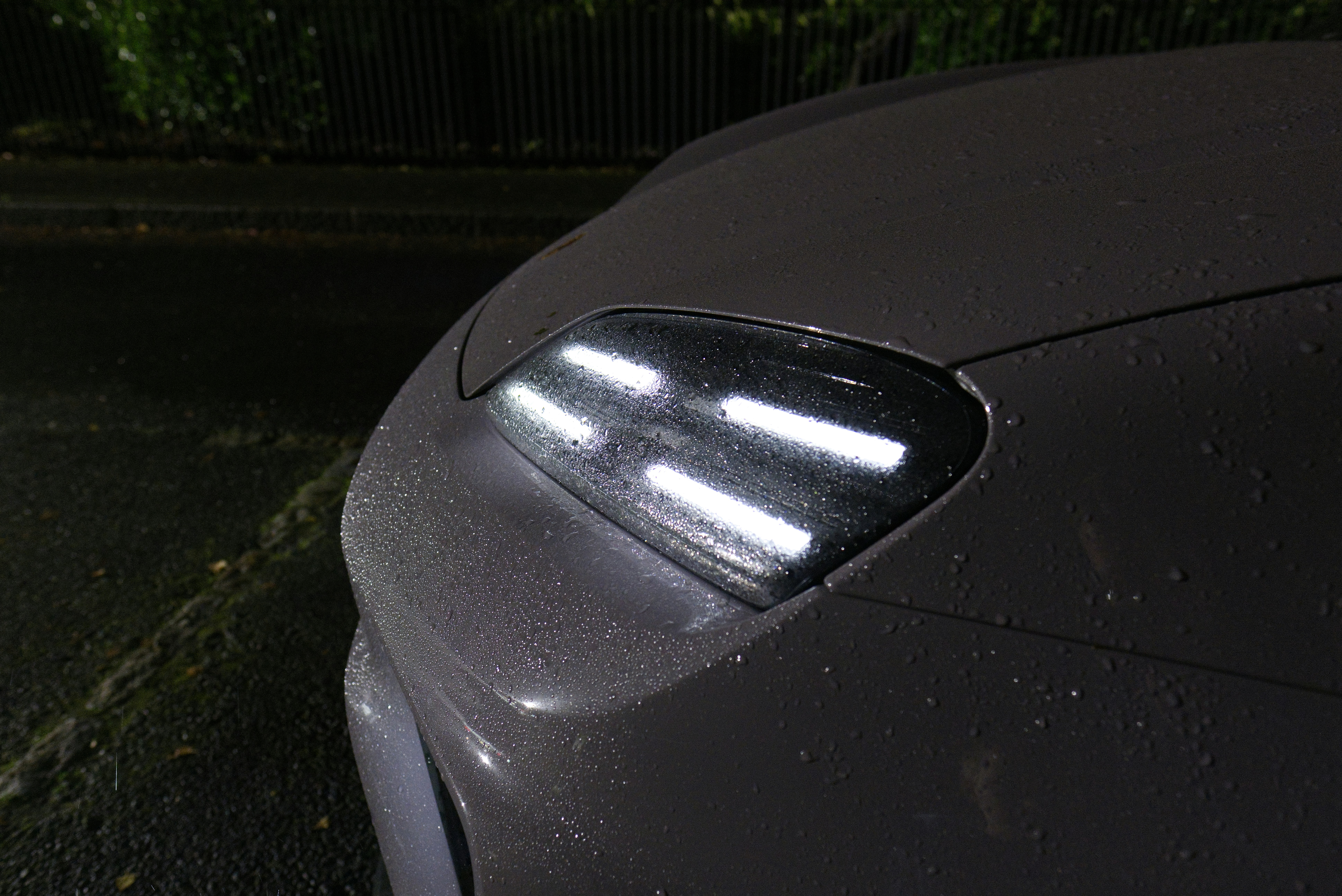 Nocturnal Sheen: Rain-Dusted Car Hood Under Neon Reflections