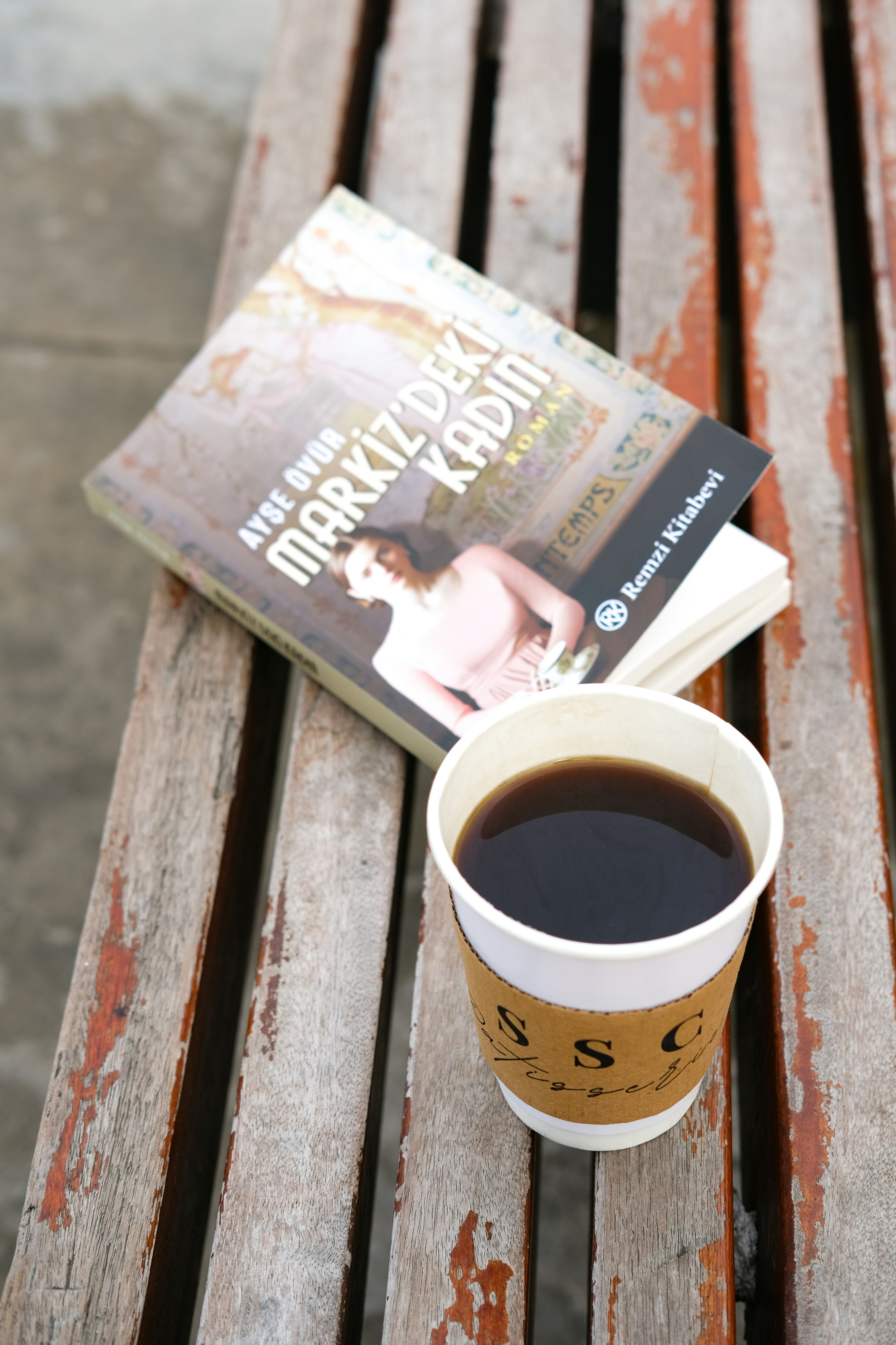 Ink and Steam: A Quiet Coffee Moment on a Weathered Bench