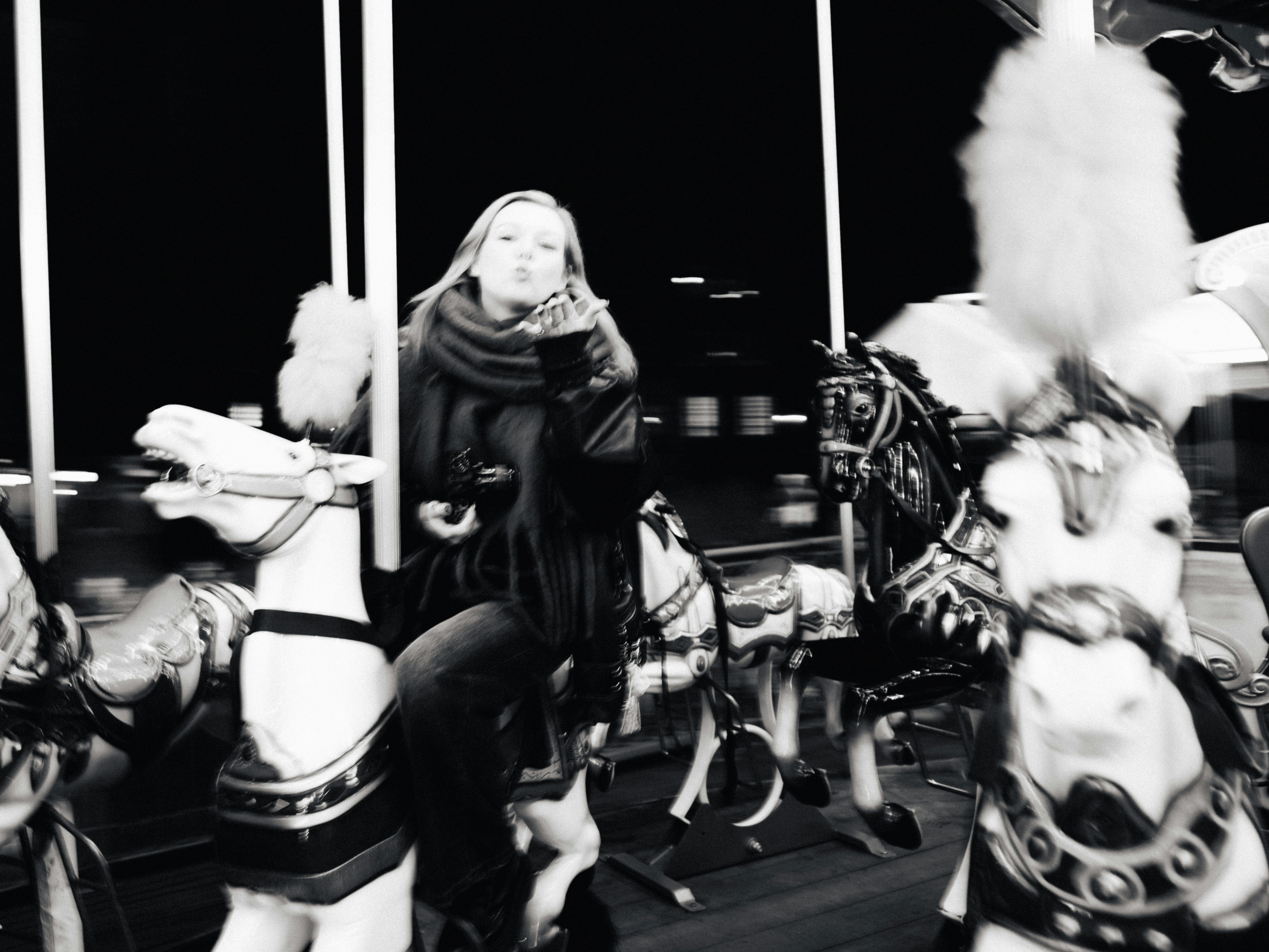 Night Carousel Kiss: A lone rider amid motion-blurred horses in monochrome