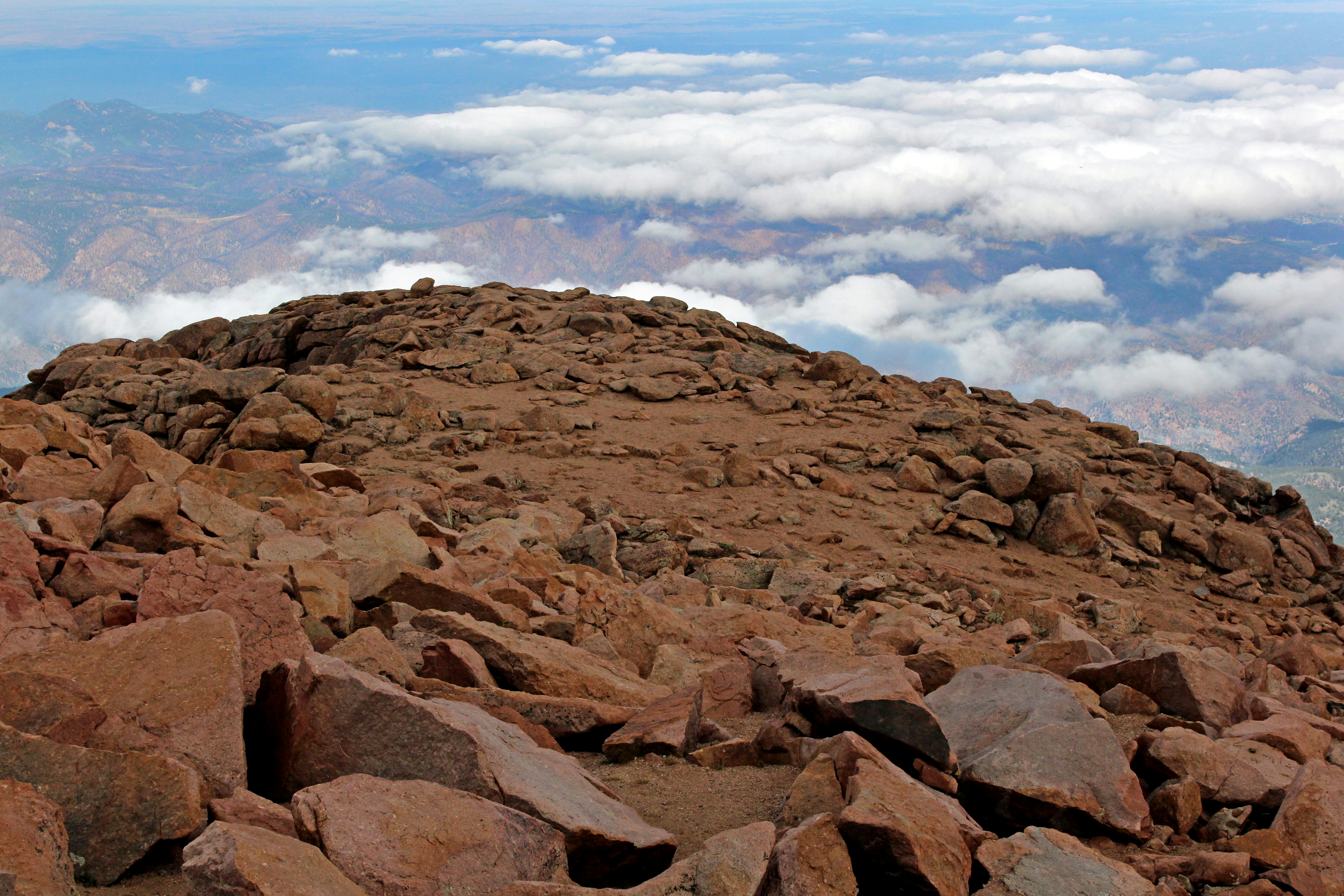 Crimson Scree Crown: Rock-Tumbled Summit Above a Veiled Sea of Clouds