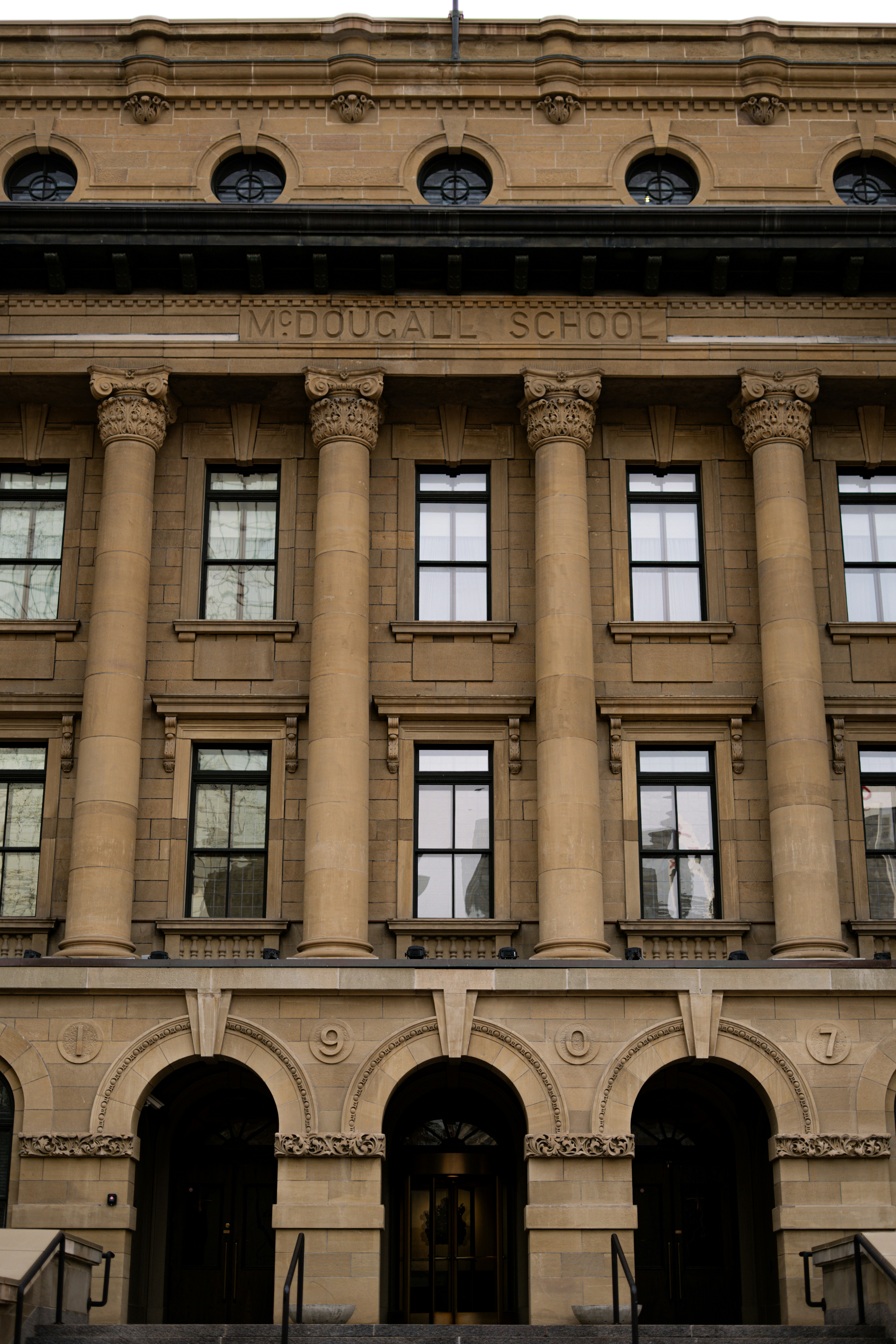Symmetrical Stone Facade: Columns, Arches, and the McDougale School