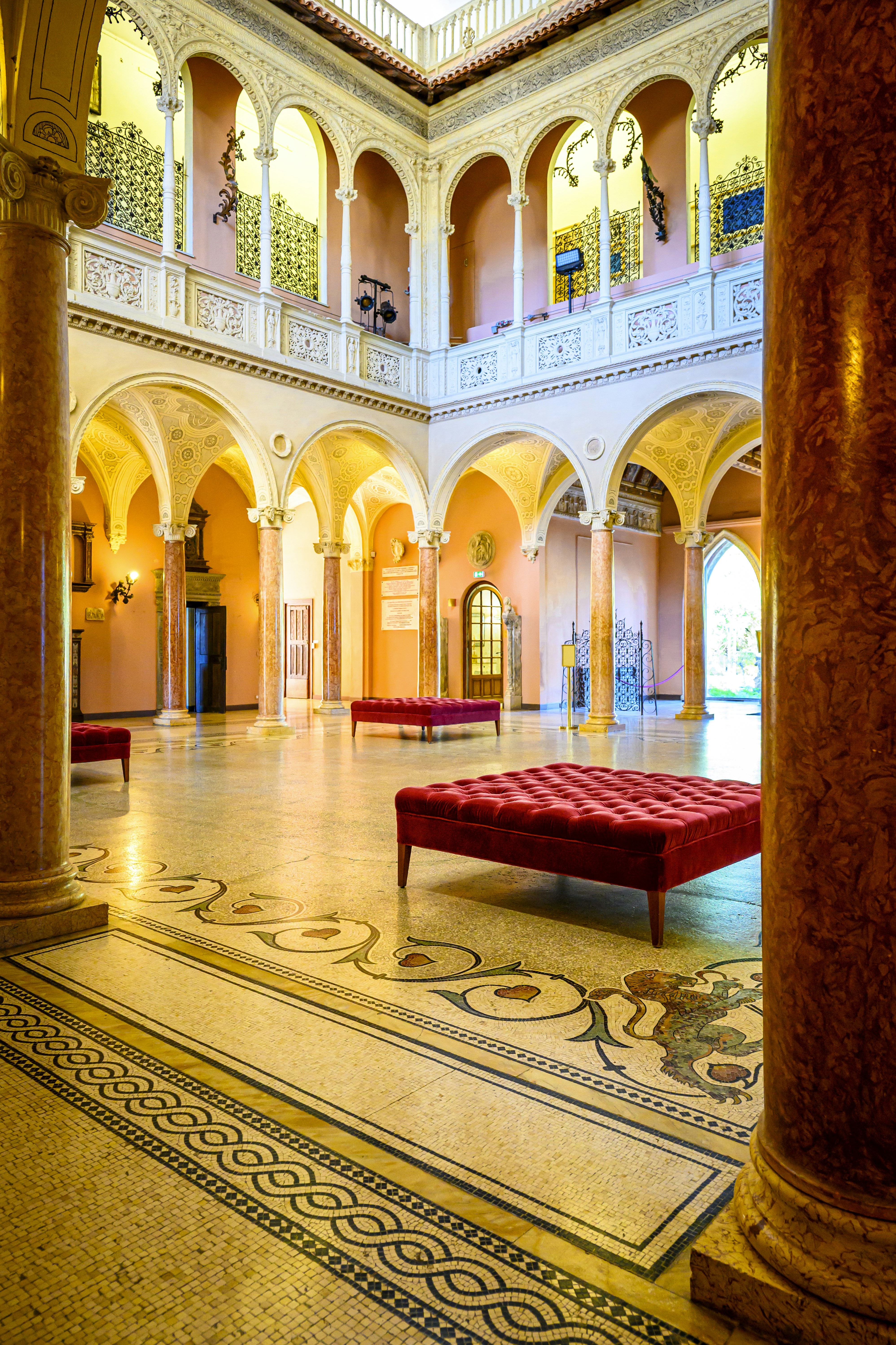 Red Velvet Bench under Amber Arches: Quiet Grandeur in a Marble Hall
