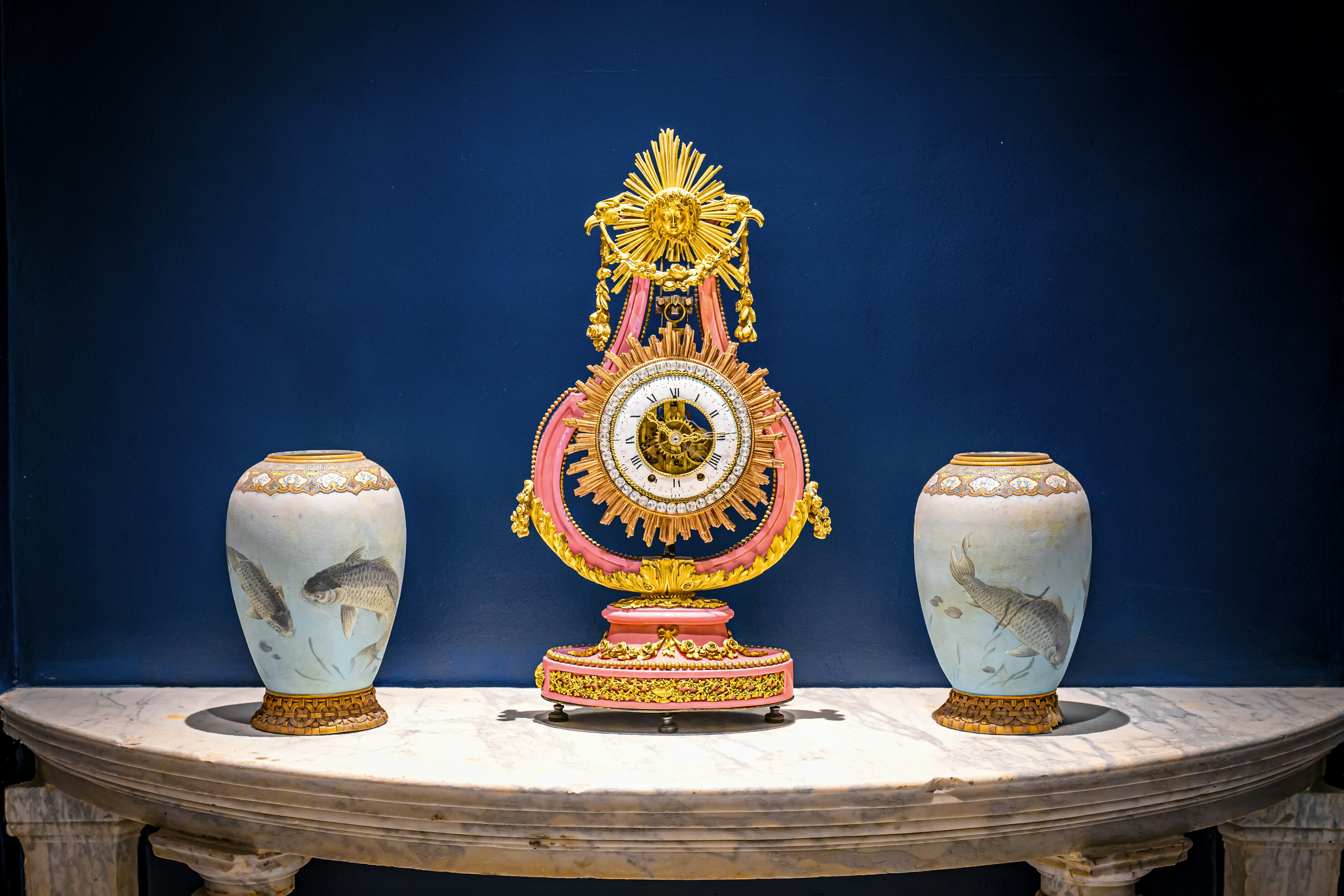 Sunburst Clock at Center: Gold Ornament on Marble Table with Cerulean Vases