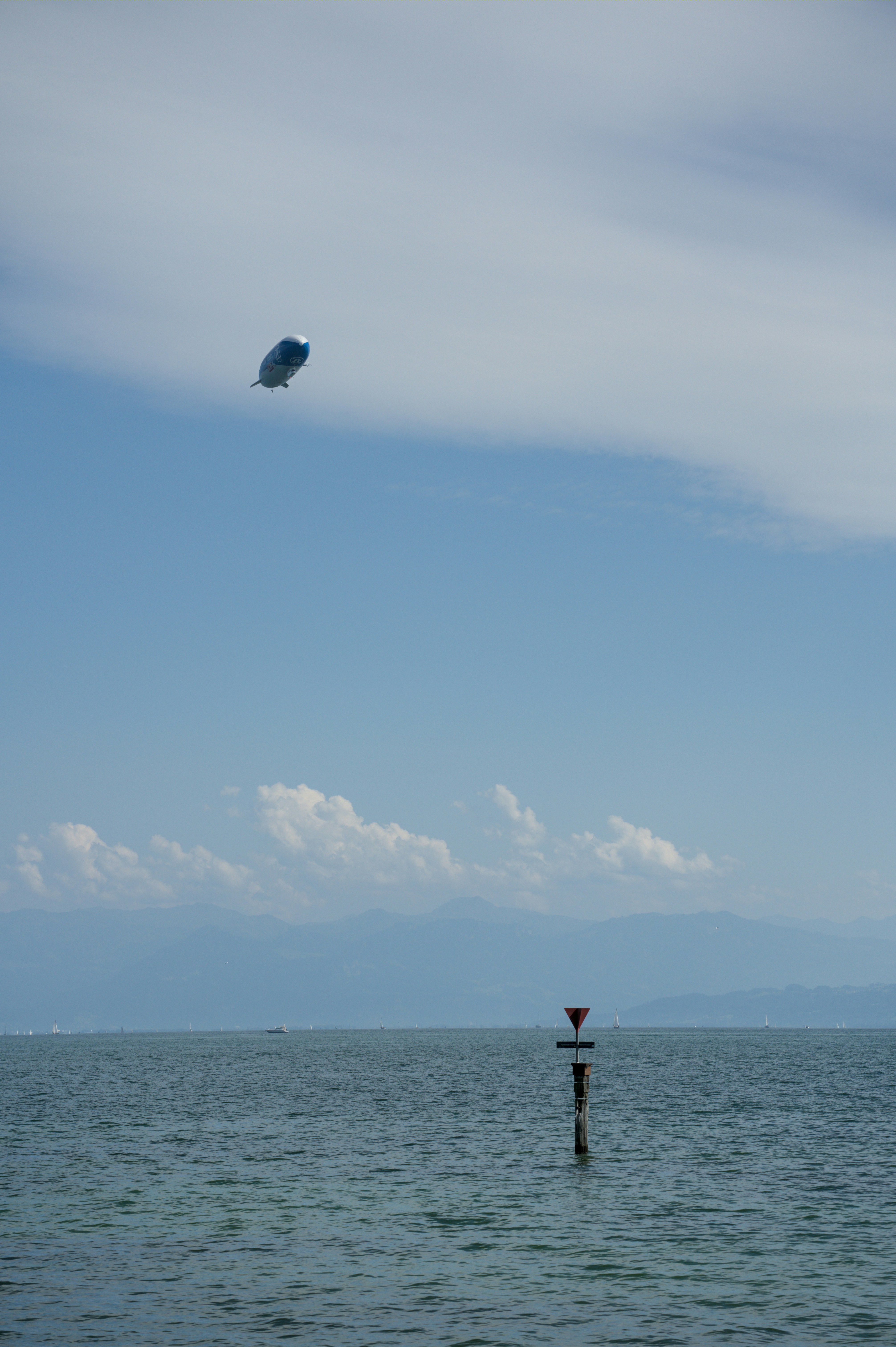 Blue Speck Hovering Over a Calm Sea with Distant Mountains