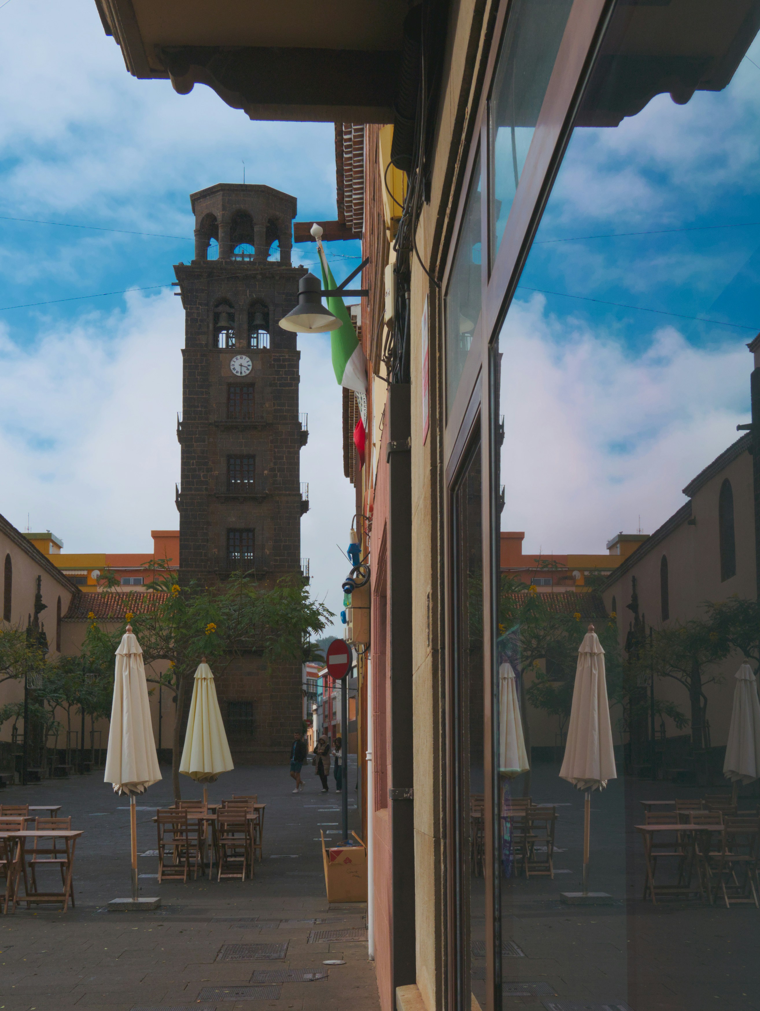 Clock Tower Mirage: Brick Heritage Framed by a Glass-Front Street