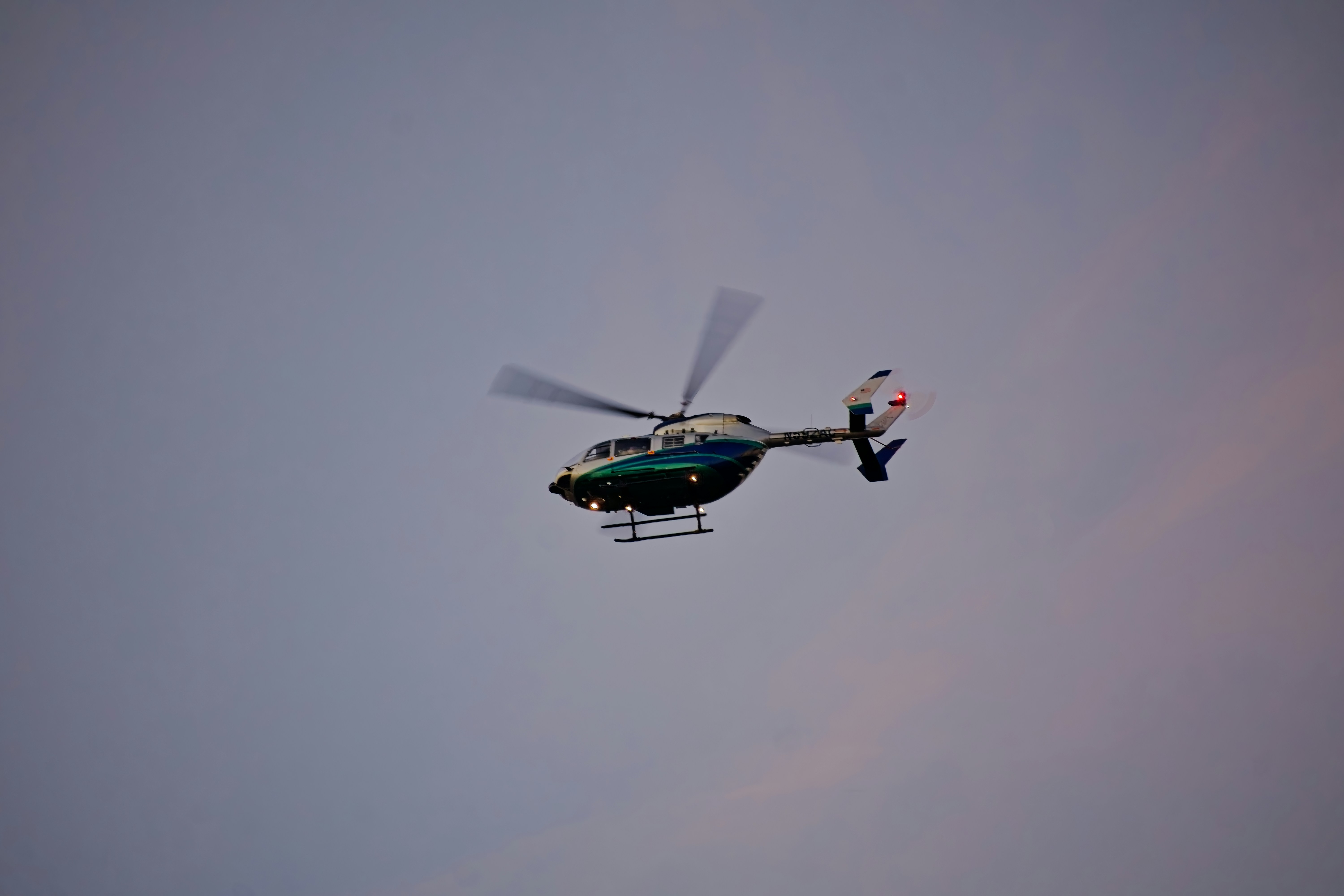 Dusk Glide Over Teal Skies: A helicopter in soft twilight