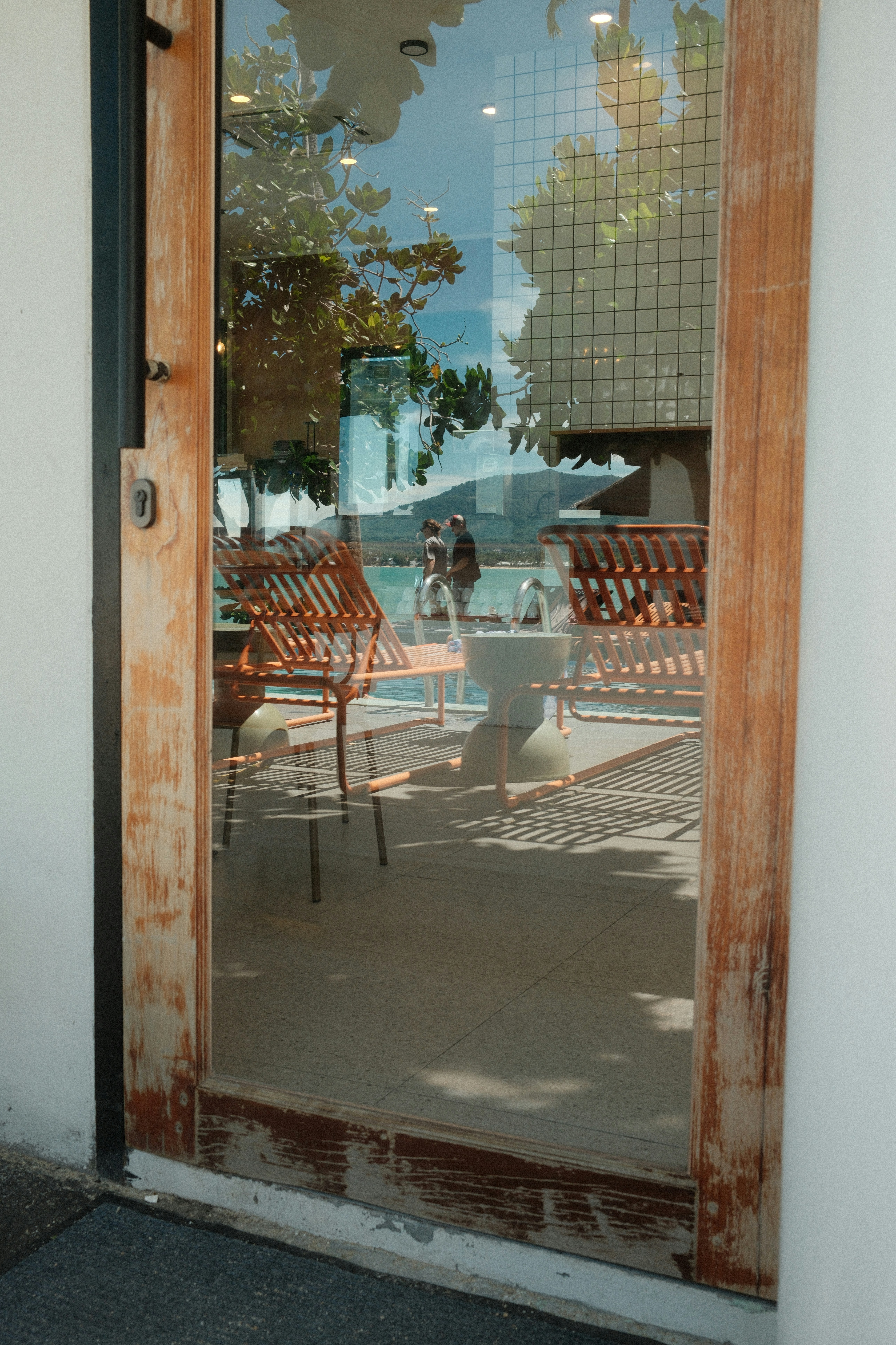 Doorway Reflections by the Pier: Orange Chairs and a Waterfront Silhouette