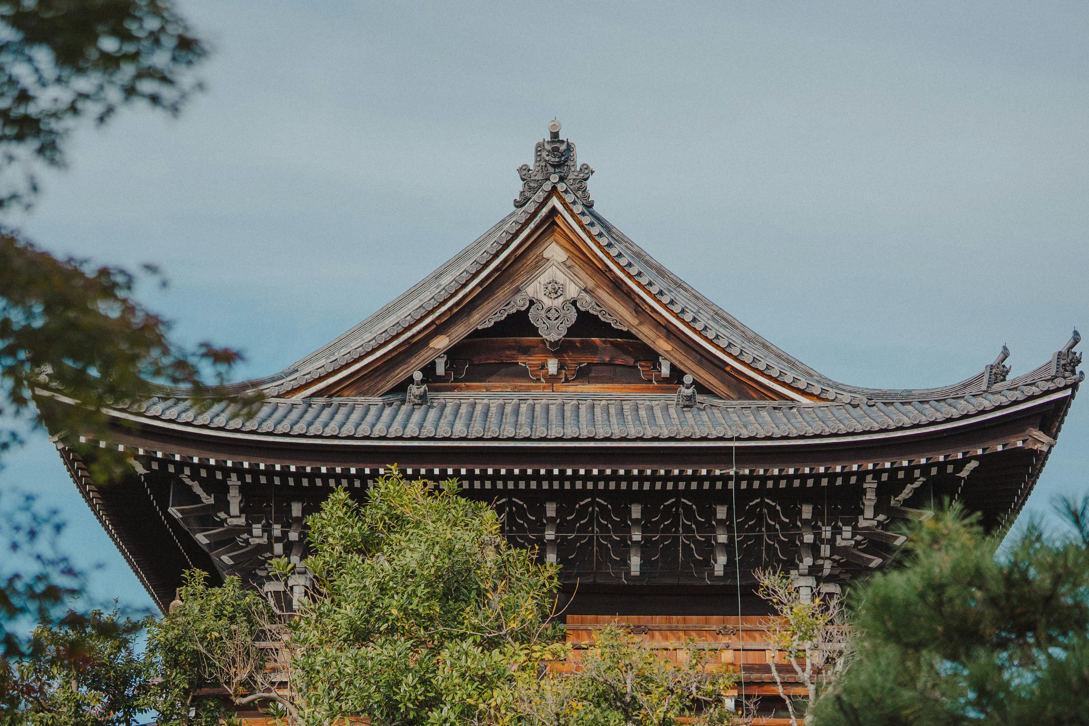Curved wooden rooflines of a traditional Japanese temple against a pale sky