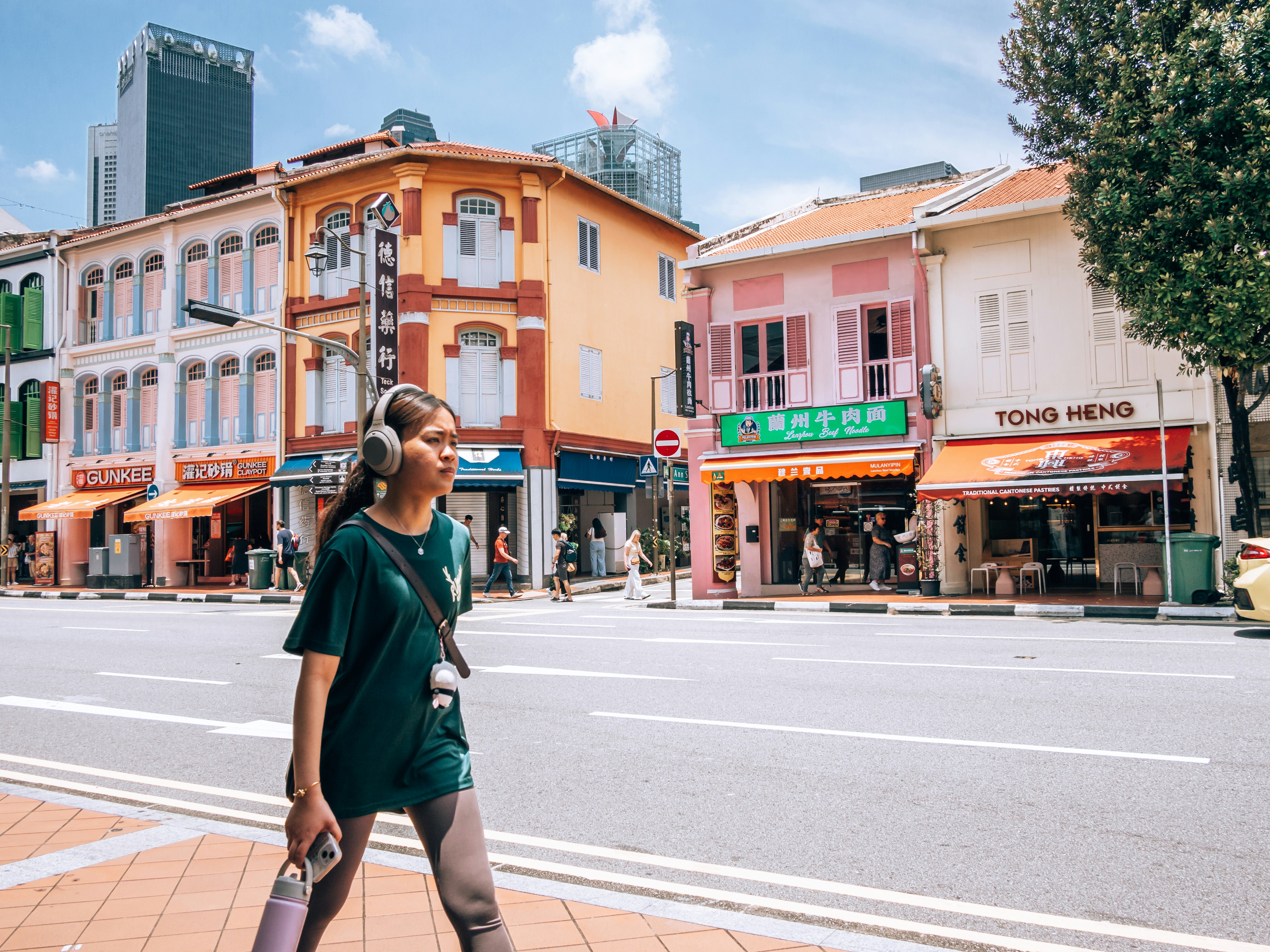 Pastel Streetscape: a lone pedestrian steps past pastel shophouses