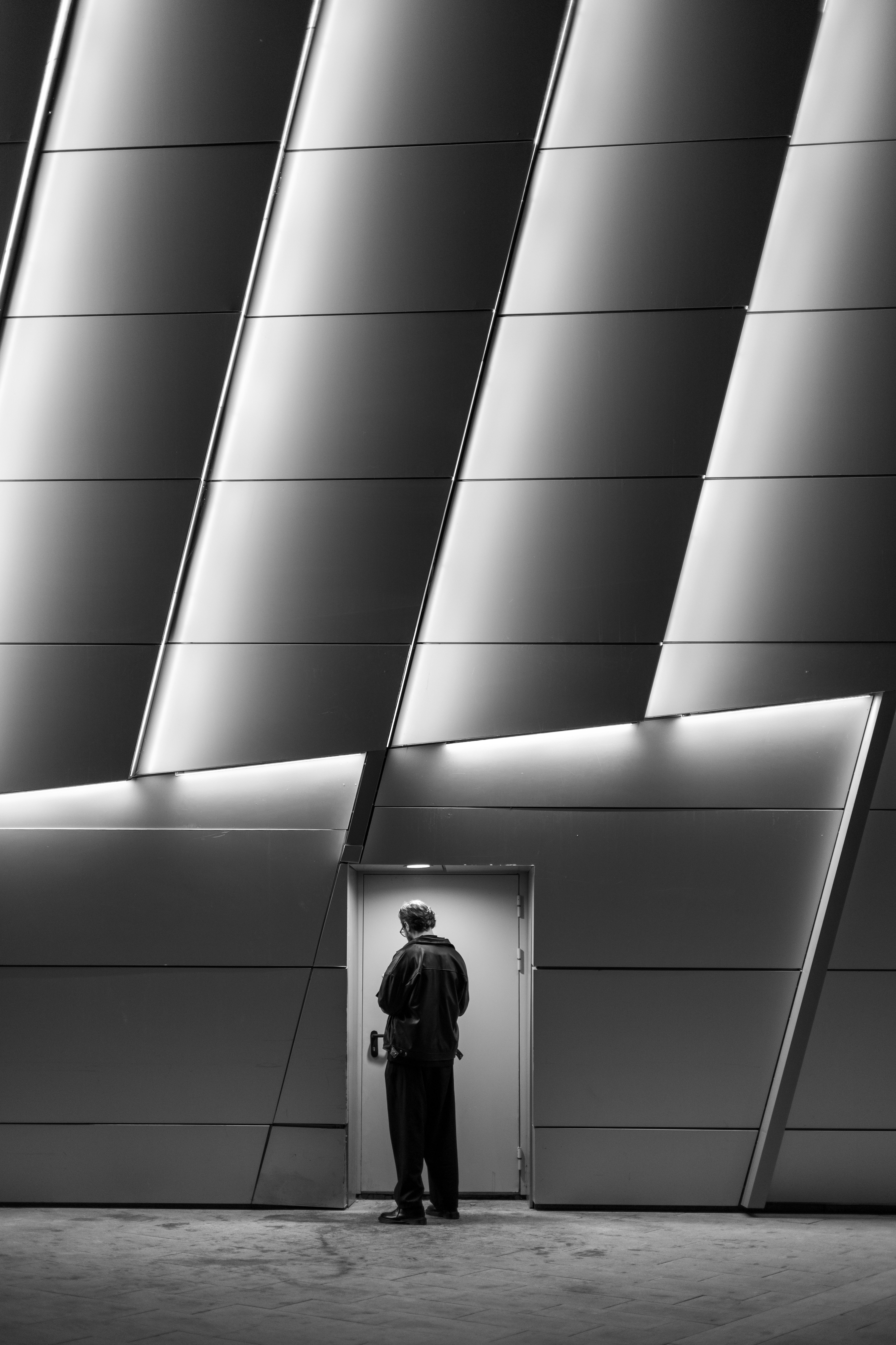 Threshold of the Faceted Wall: A Lone Figure at the Door