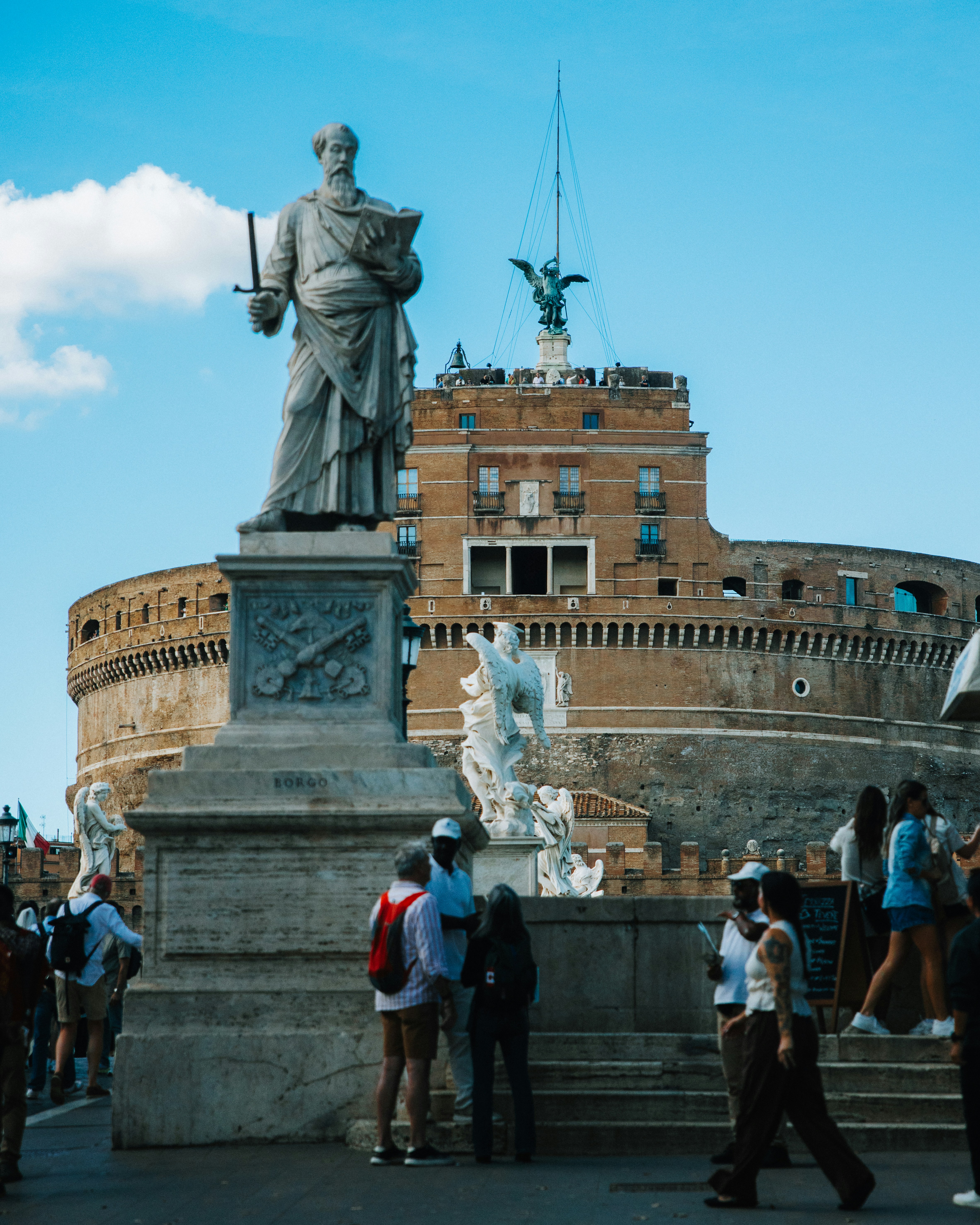 Stone Sentinel Over Rome: Marble Statue Framed by Castel Sant’Angelo