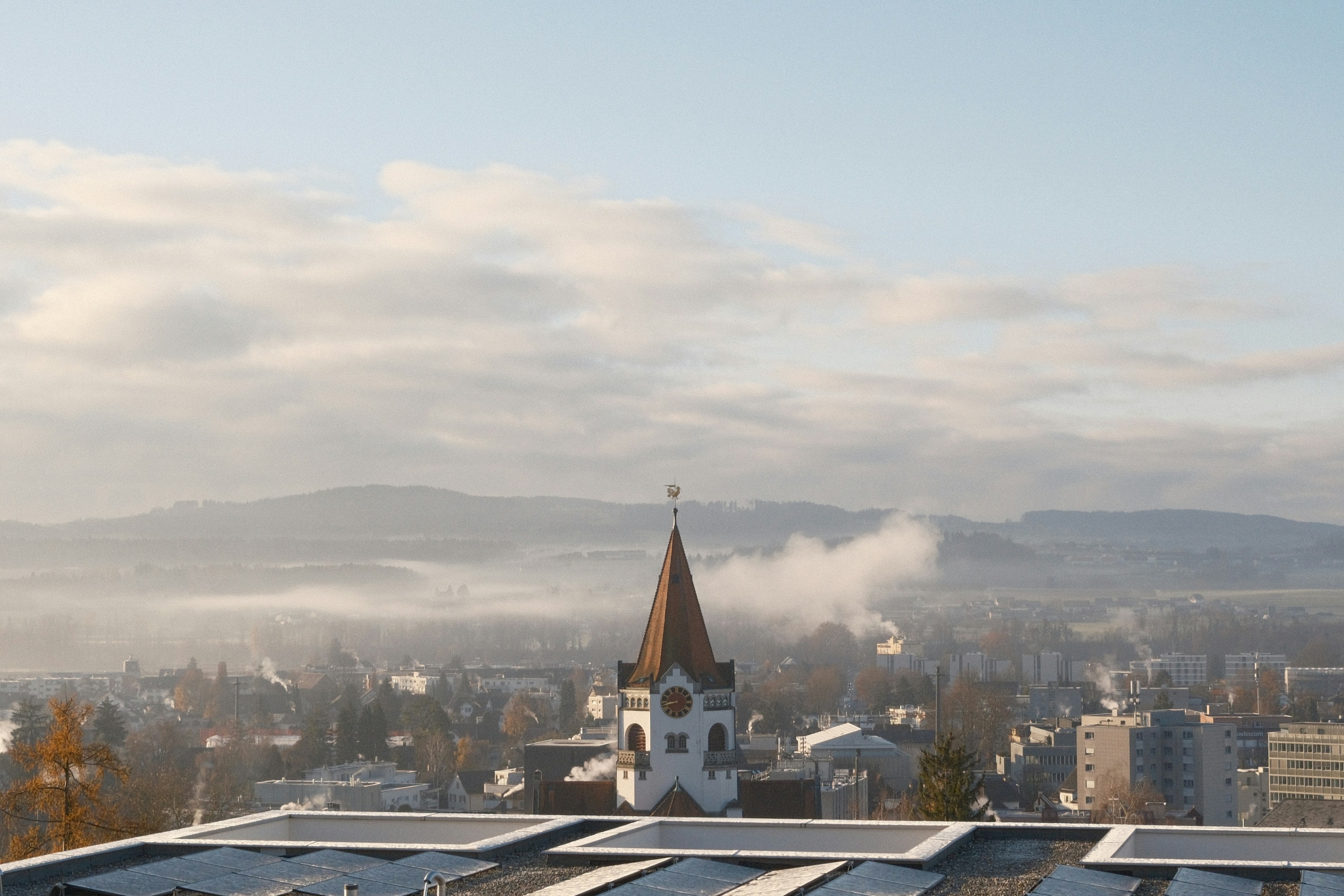 Dawn Mist Over the City: Clock-Topped Spire Above Rooftops