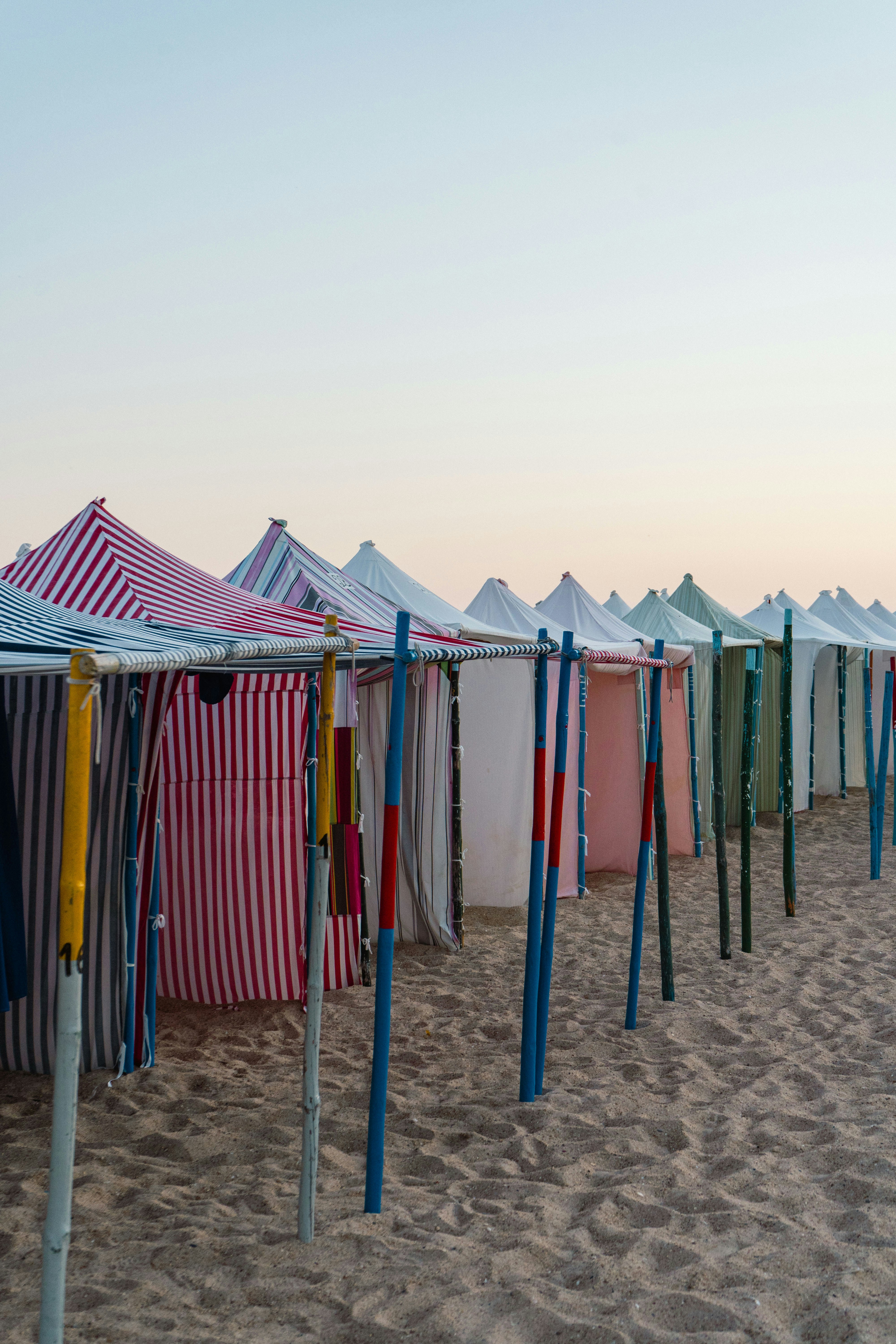 Row of Striped Beach Cabins Stretch Across a Tranquil Shore at Dusk