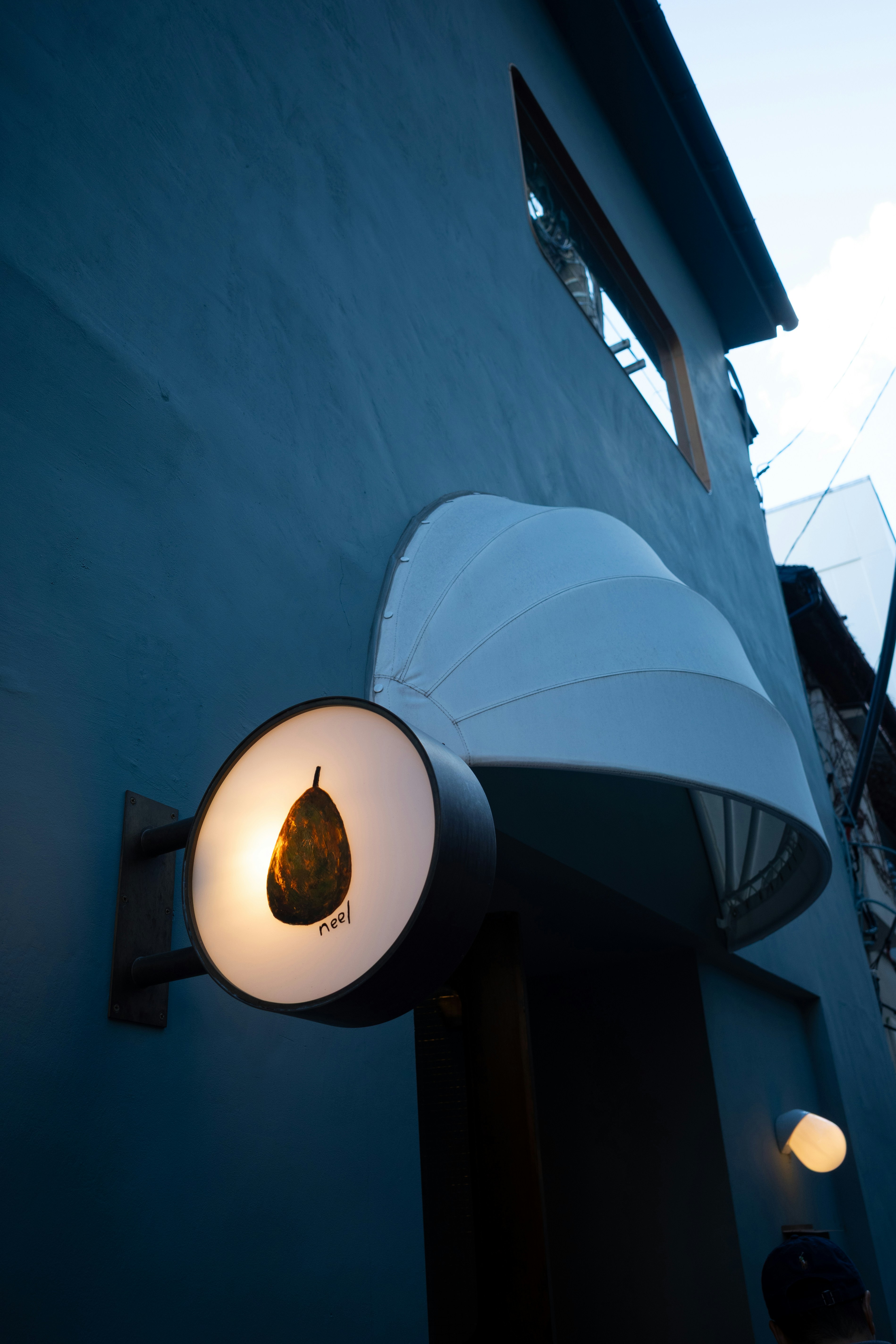 Pear Lantern on a Cobalt Facade Beneath a Curved Canopy